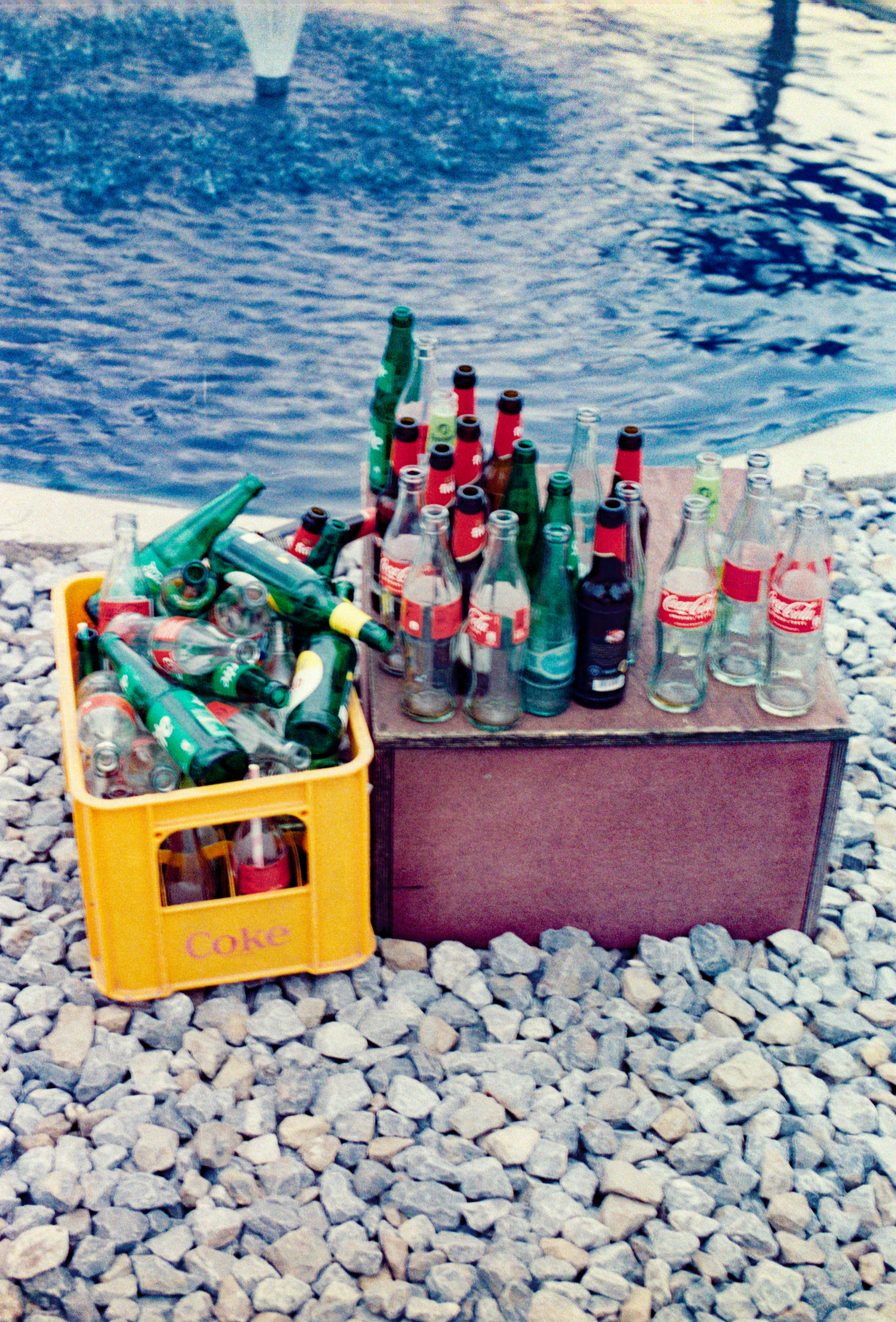 Glass bottles in a yellow crate near a fountain