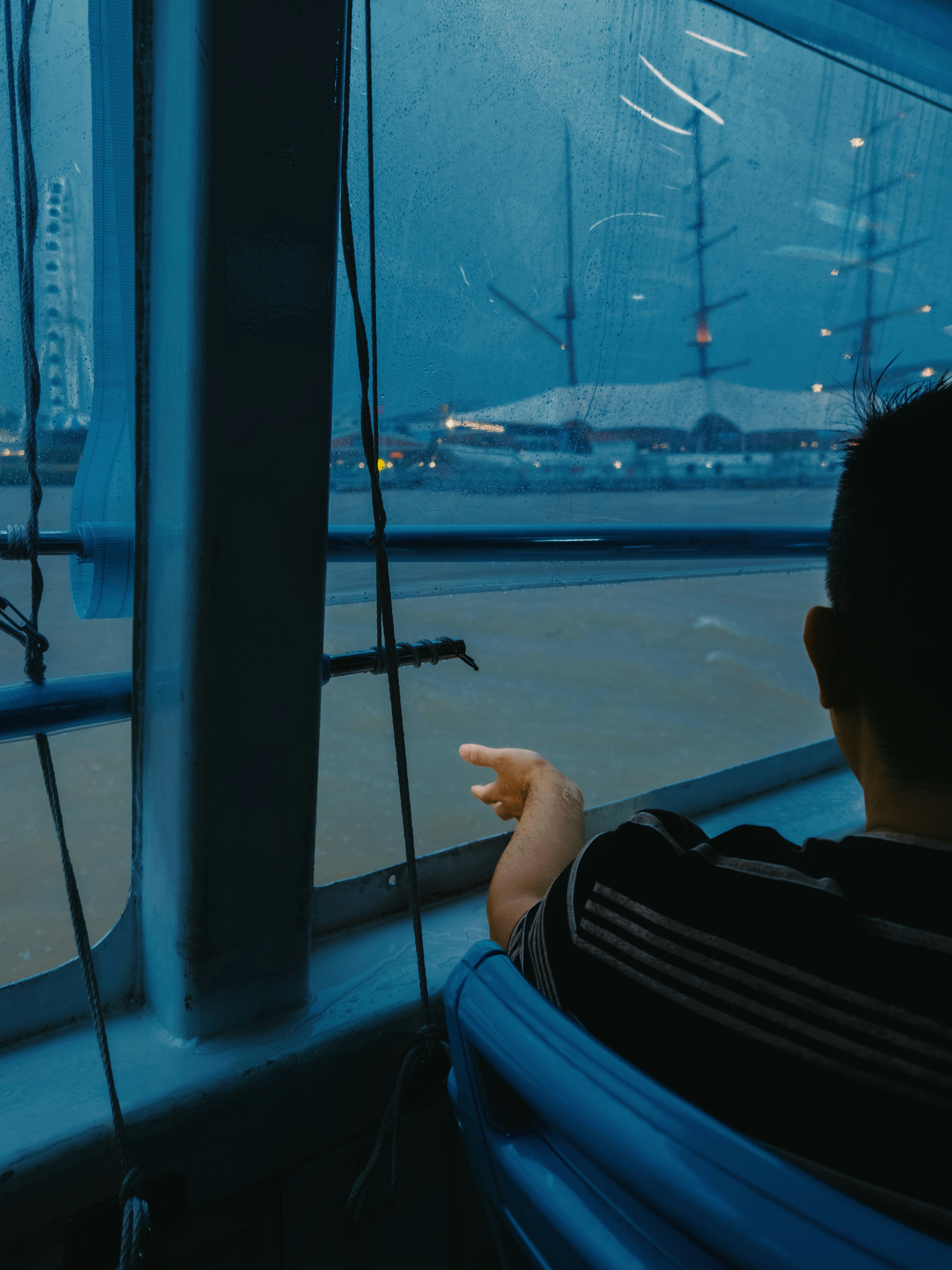 Bangkok river cruise during heavy rain | Person looking out window at docked ships