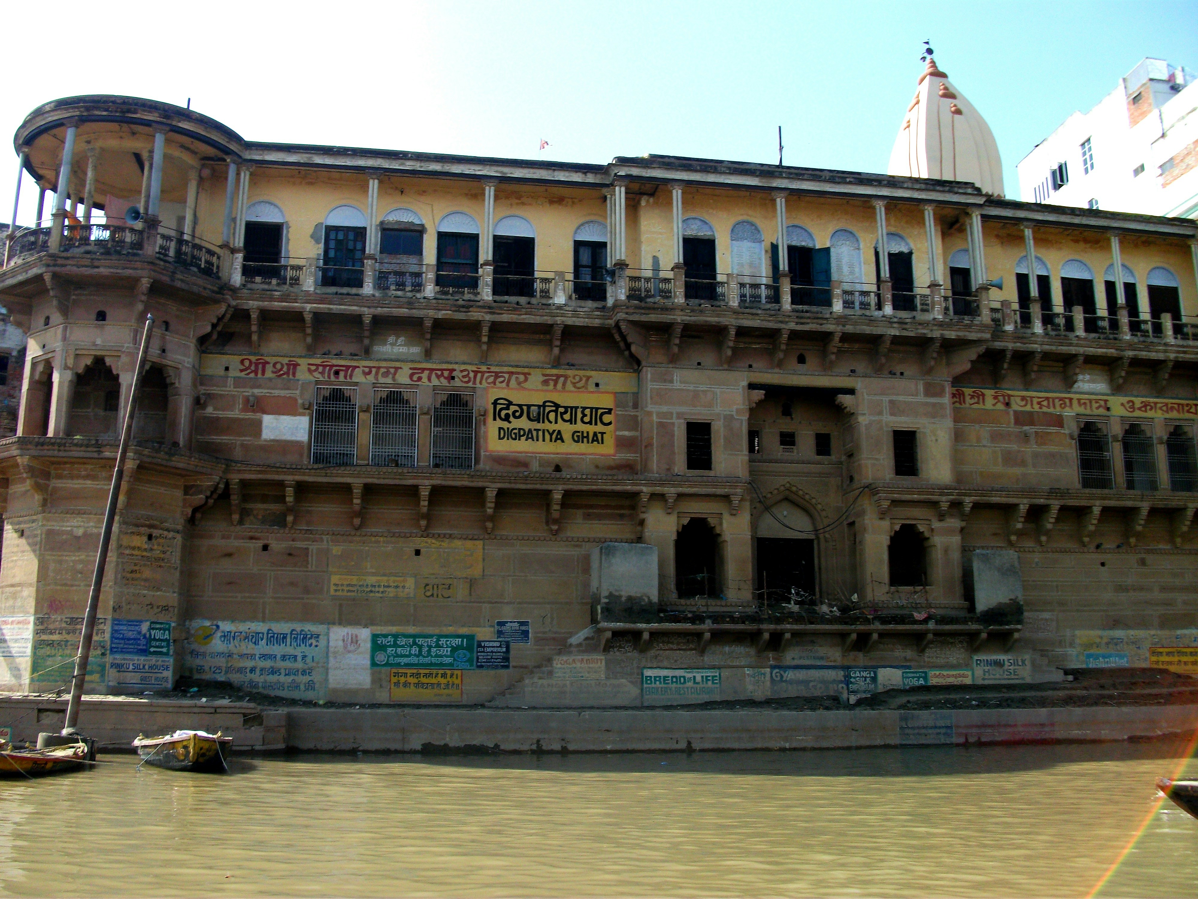 Varanasi is the first and last City on Earth. Every Day Many Pilgrims and Devotees from All Around the World Visit Varanasi (Khaasi). People Take Bath on the Ghats of Varanasi in the Holy River Ganga and Worship the Destroyer Shiva. Kala Bhairav is the Protector of this City. Ganga Devi, The Mighty Godess Force of Sacred Water from Heaven to Earth. To Control Her Flow Smoothly to Earth The God of Destroyer Shiva, kept Ganga Devi on his Head and Opened a Small Hair Lock in Which the Flow of Ganga Devi was controlled smoothly to earth. Ganga Devi is considered the Holy River of Earth. | Historic building on the bank of a river