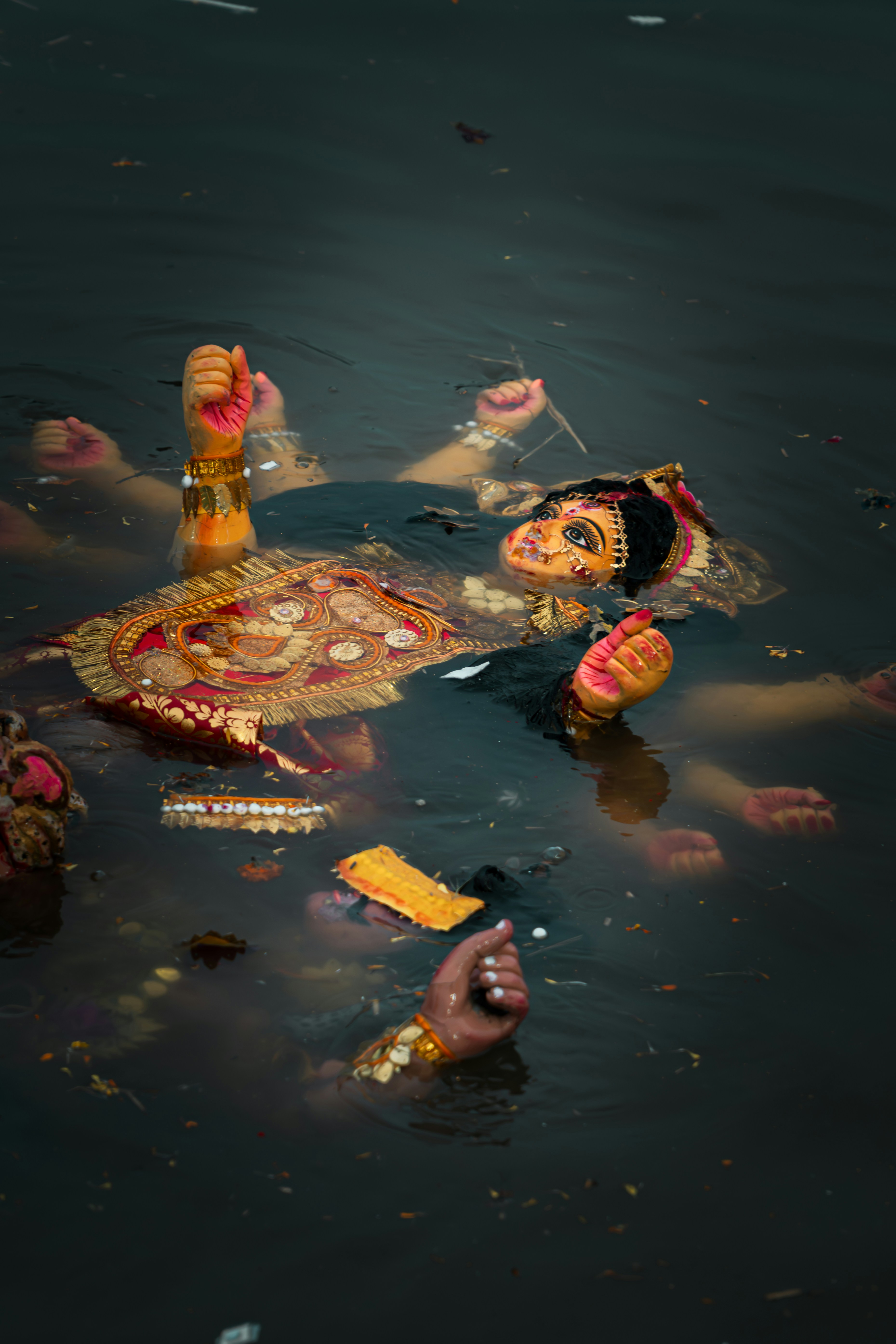 Idol submerged in dark water with debris