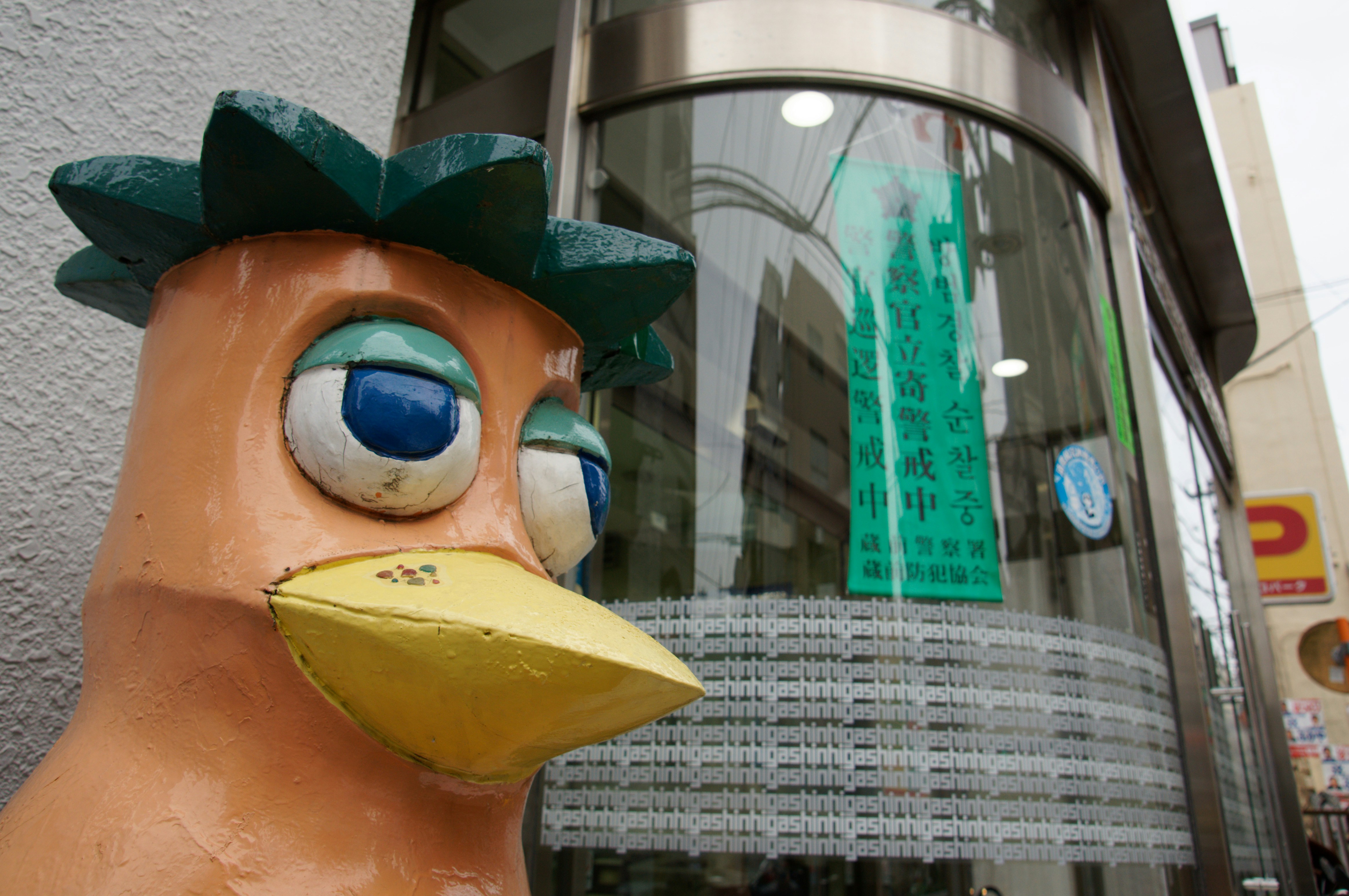 Quirky cartoon chicken statue outside modern building