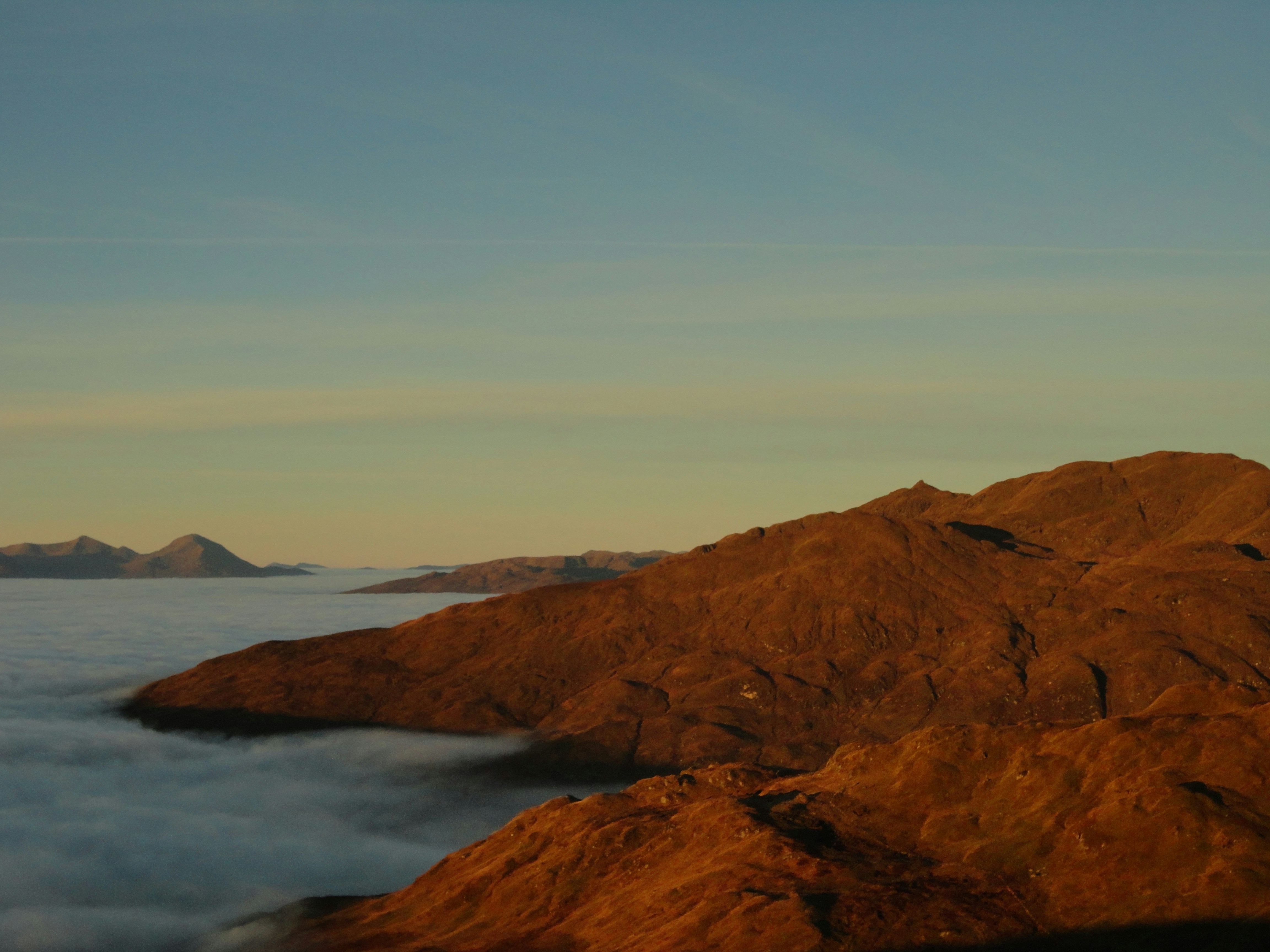 Golden mountains above sea of clouds at sunrise