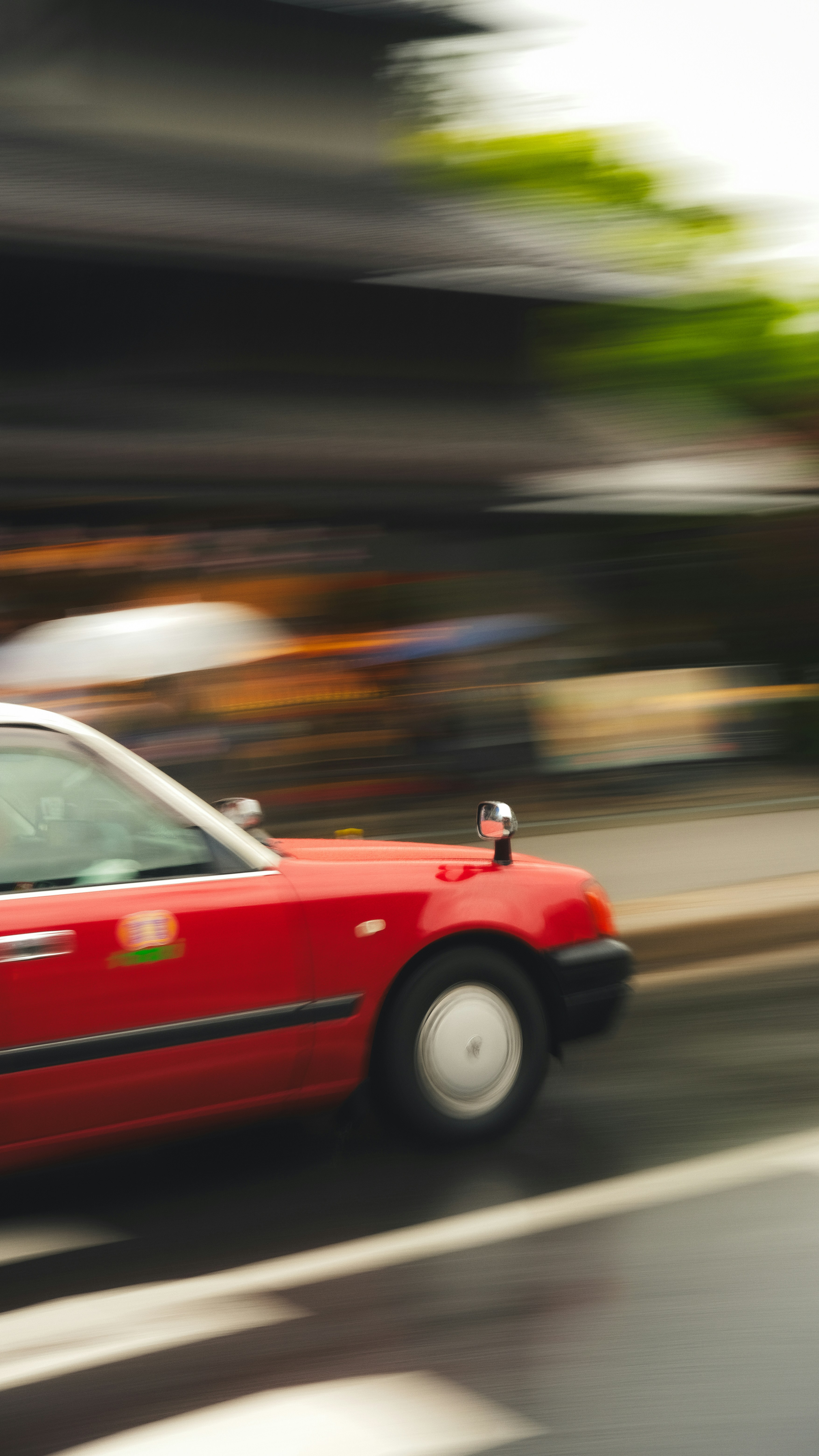 Red taxi driving fast on city street