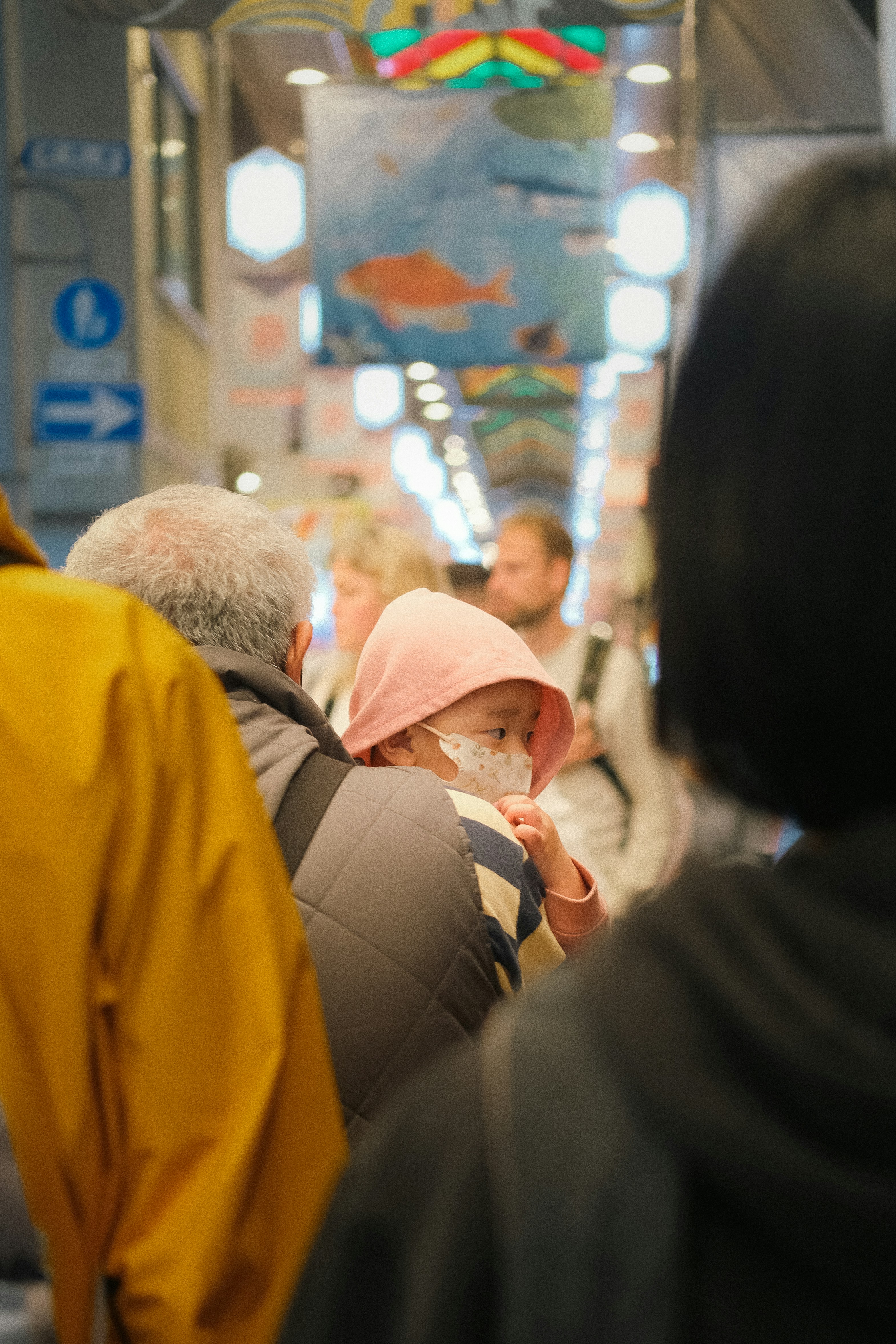 A child wearing a mask in a crowded marketplace.