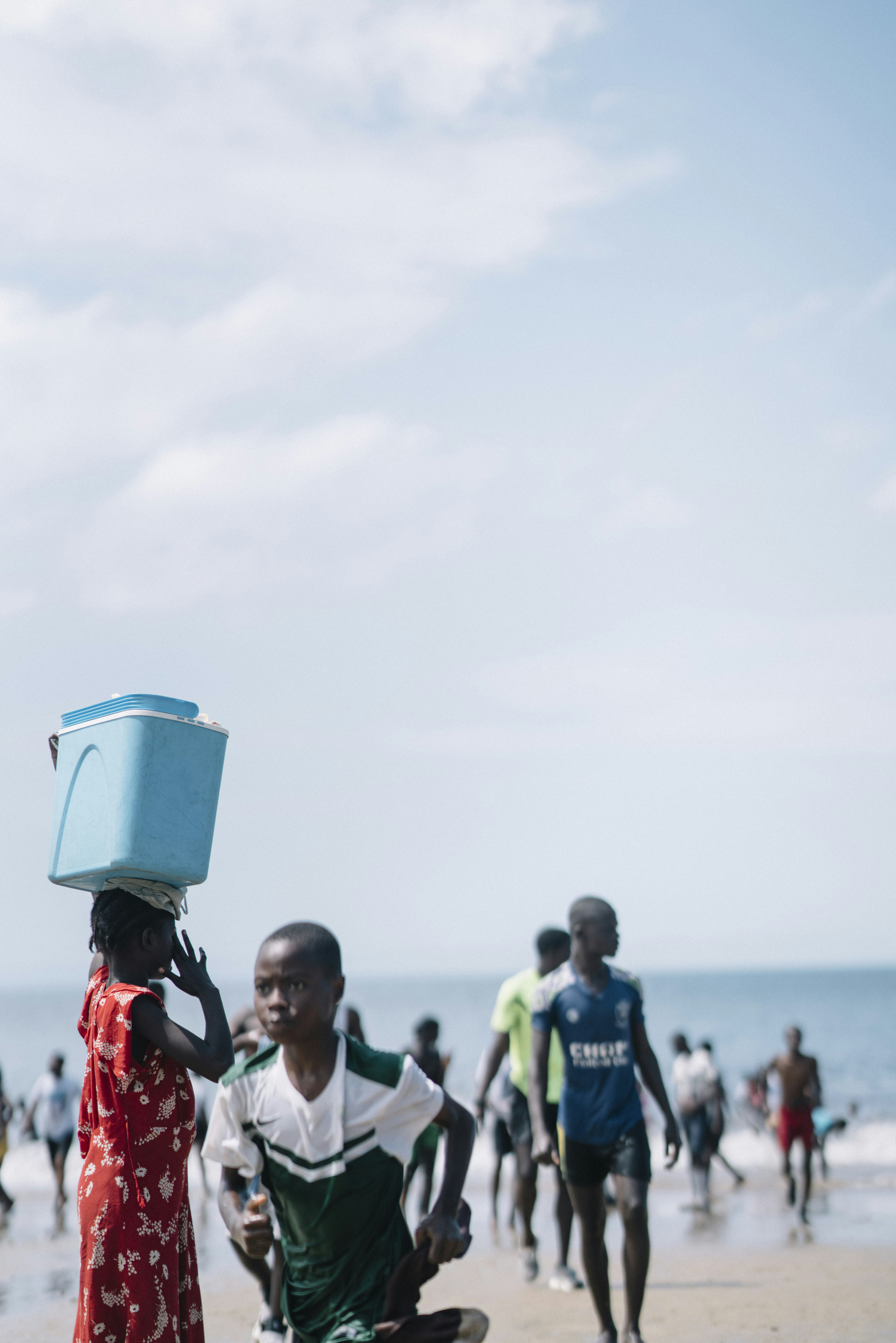 Children carrying cooler on beach near ocean