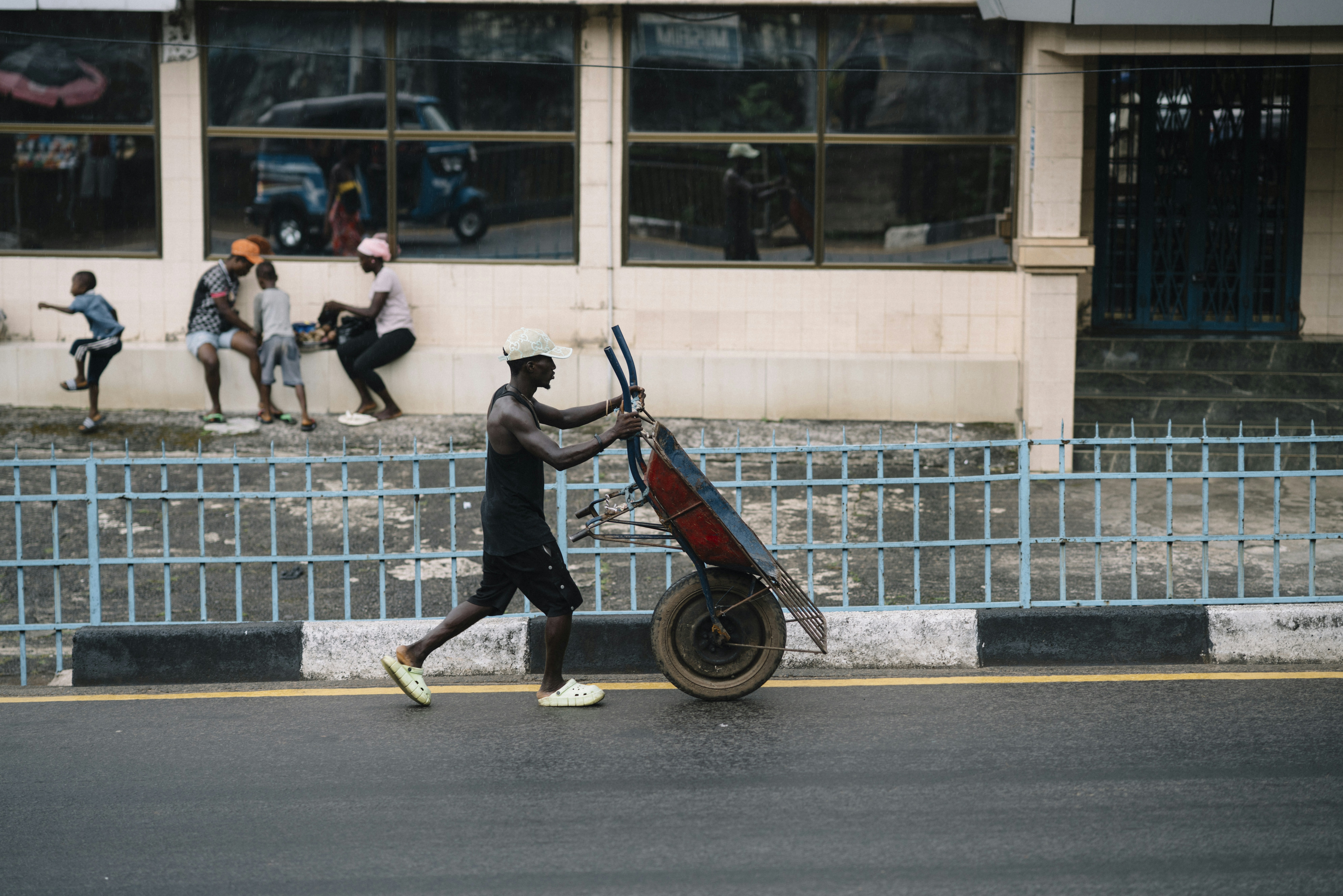 Man pushes wheelbarrow on a street