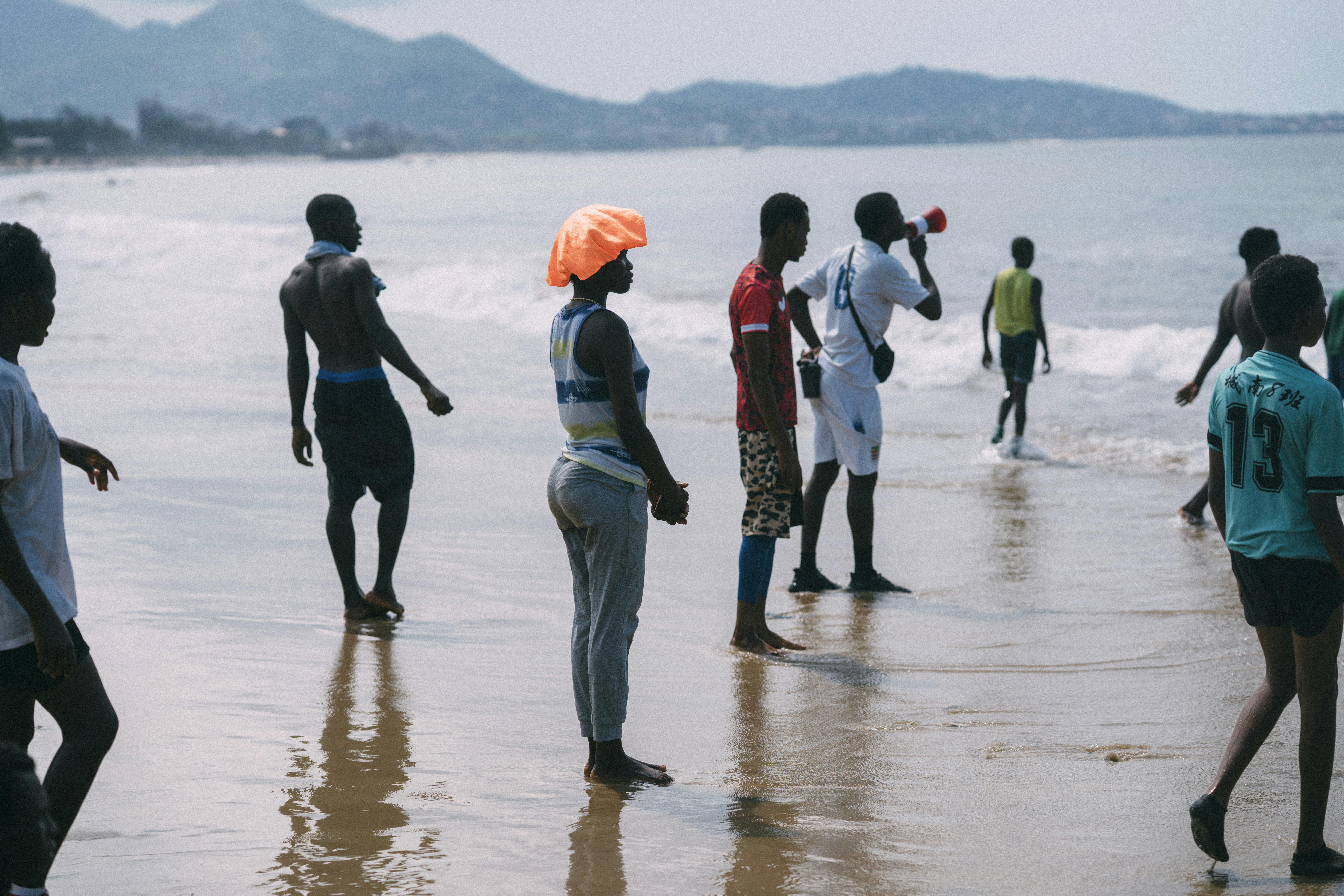 People walking on a wet sandy beach near the ocean.