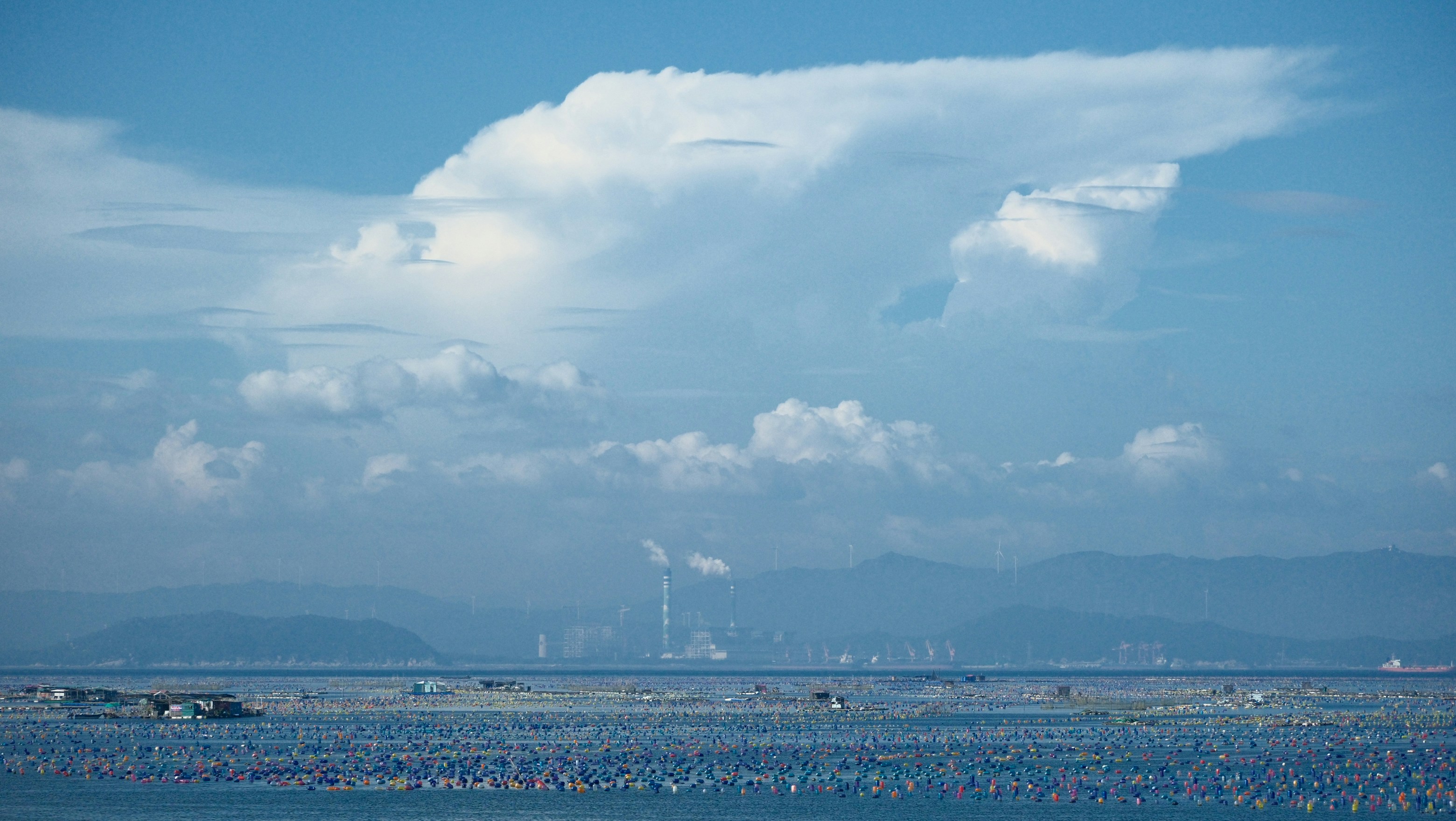 Large cloud formation over distant mountains and water
