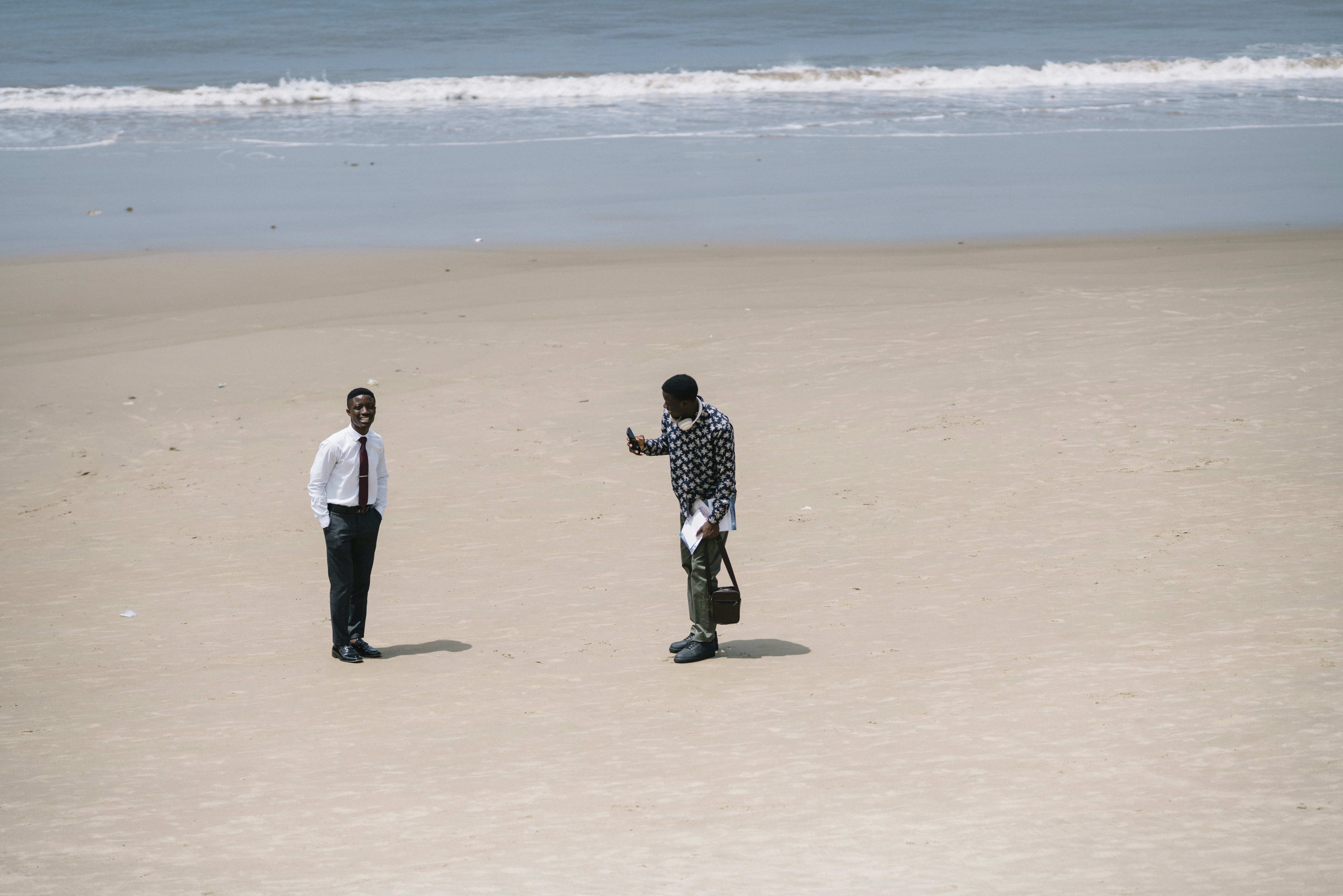Two men standing on a sandy beach near ocean