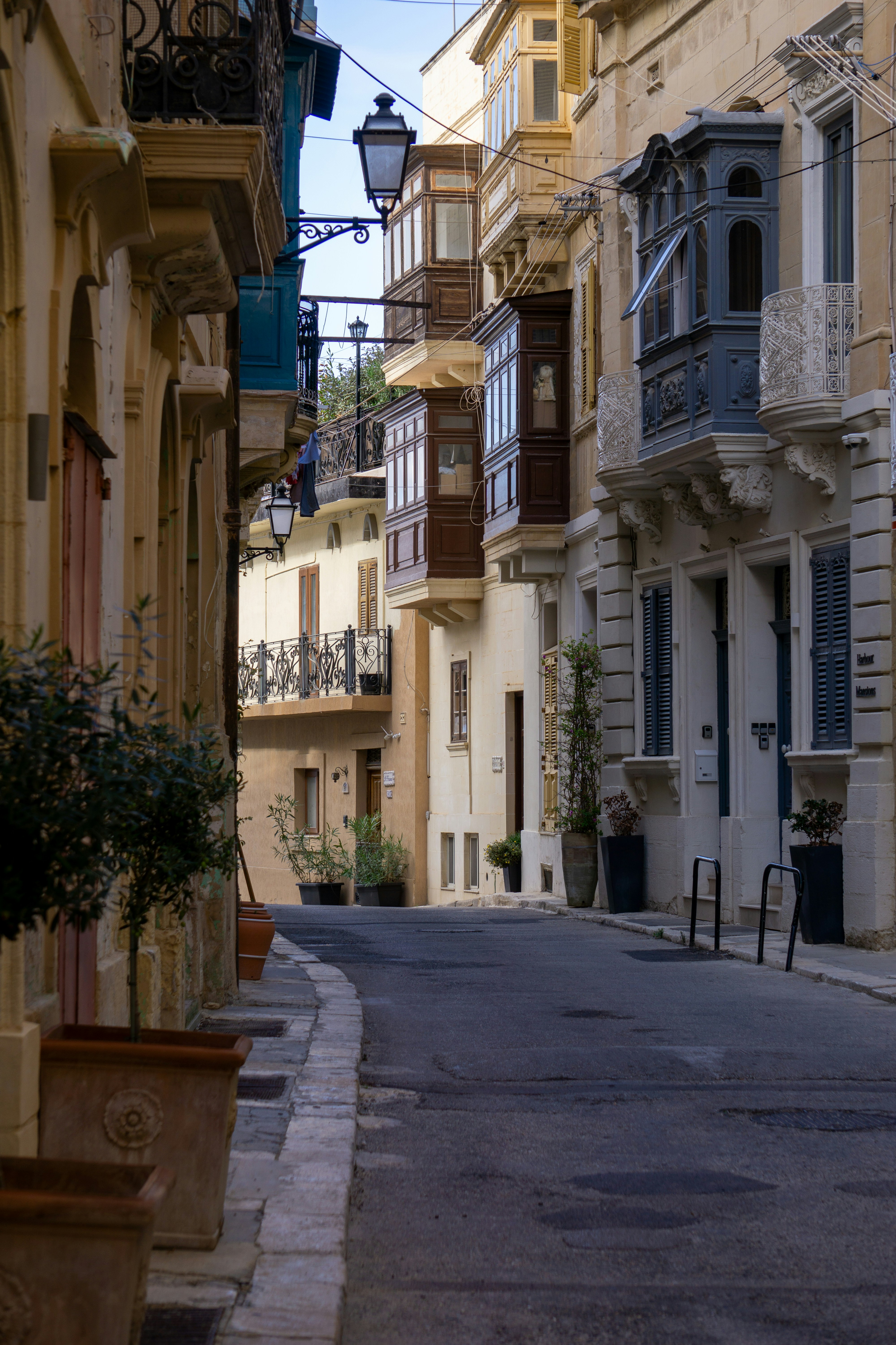 Streets of Malta | Narrow street with traditional balconies and potted plants.