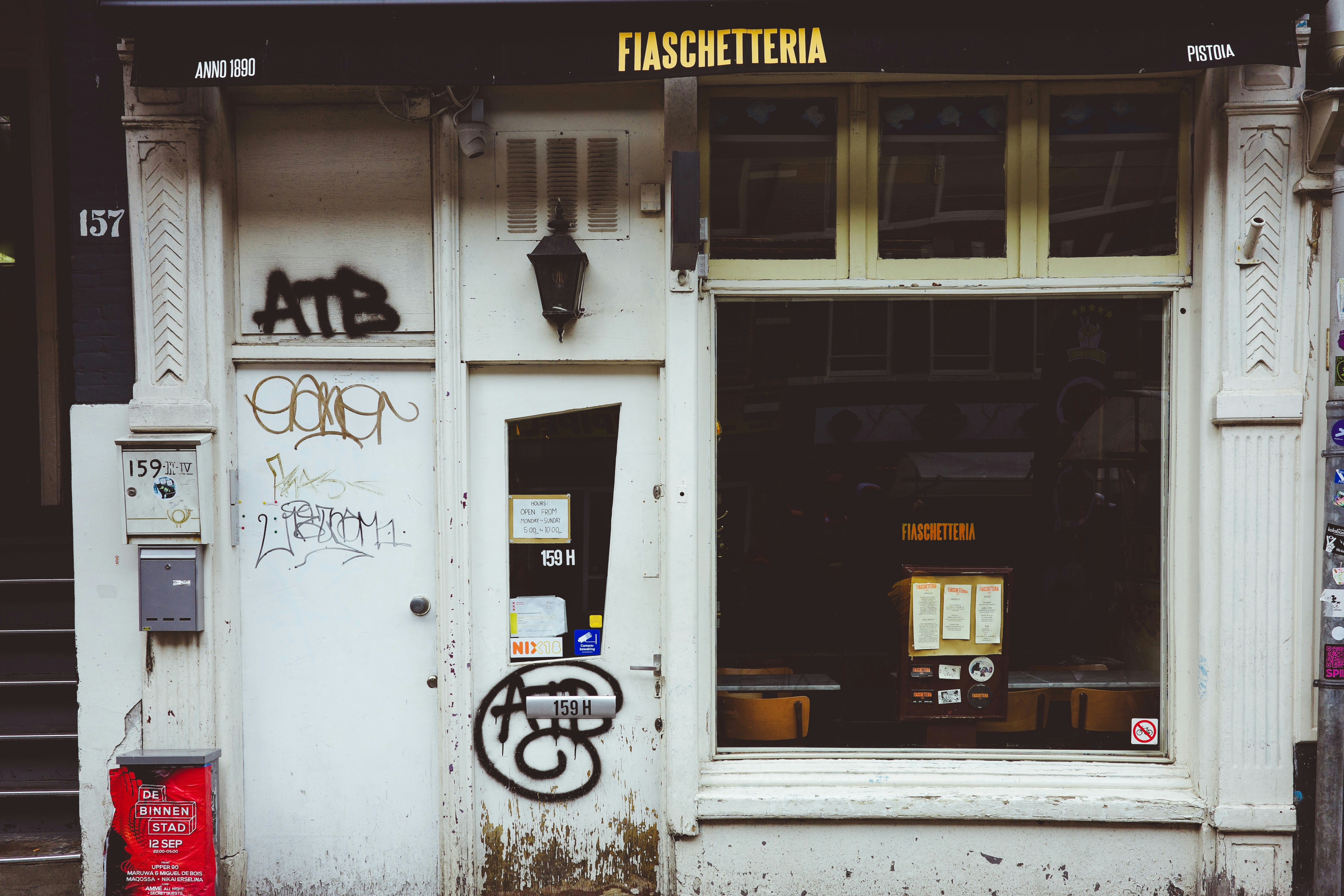 A store facade with graffiti and a sign.