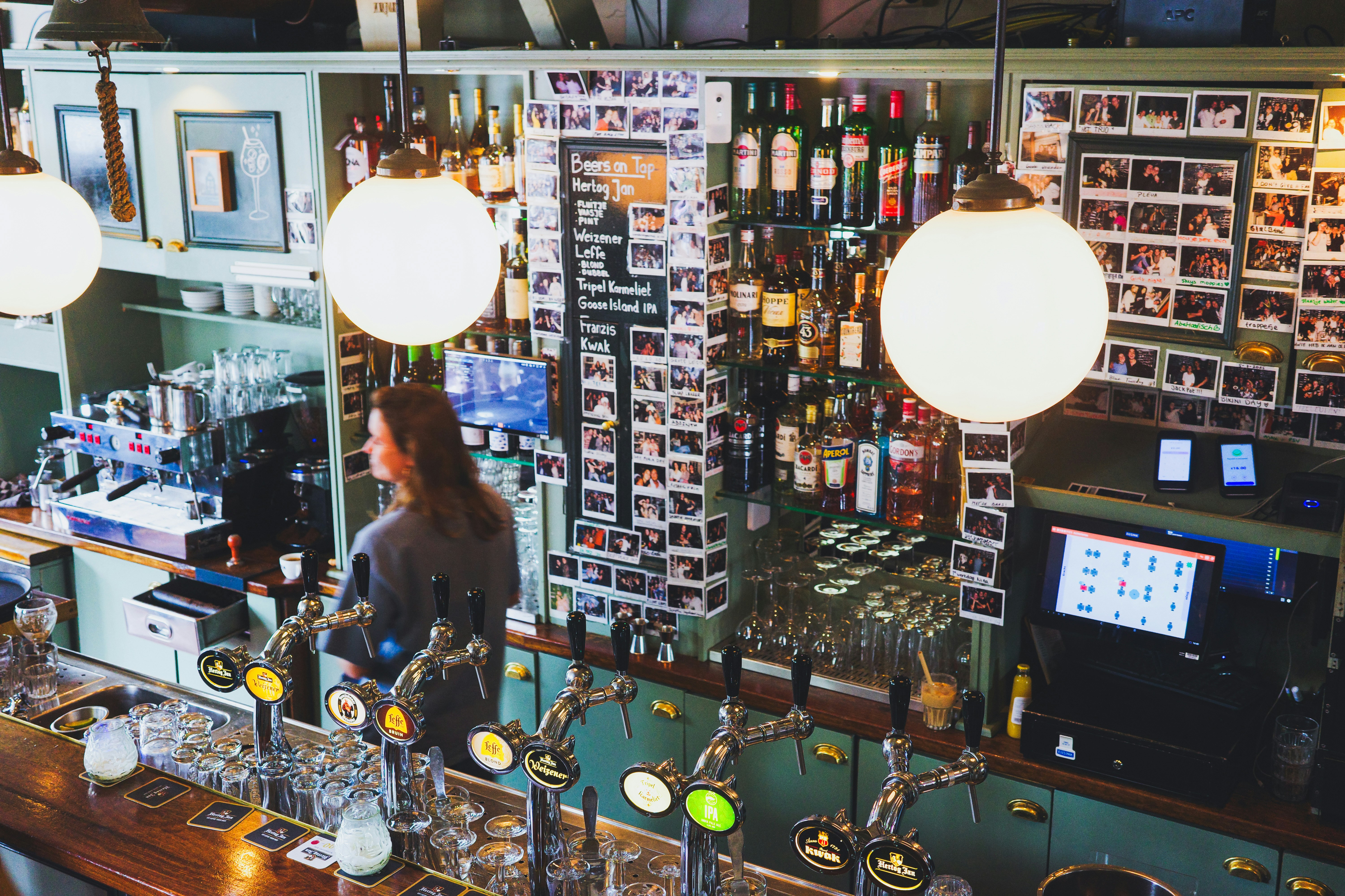 Bartender working behind a bar with bottles and taps.