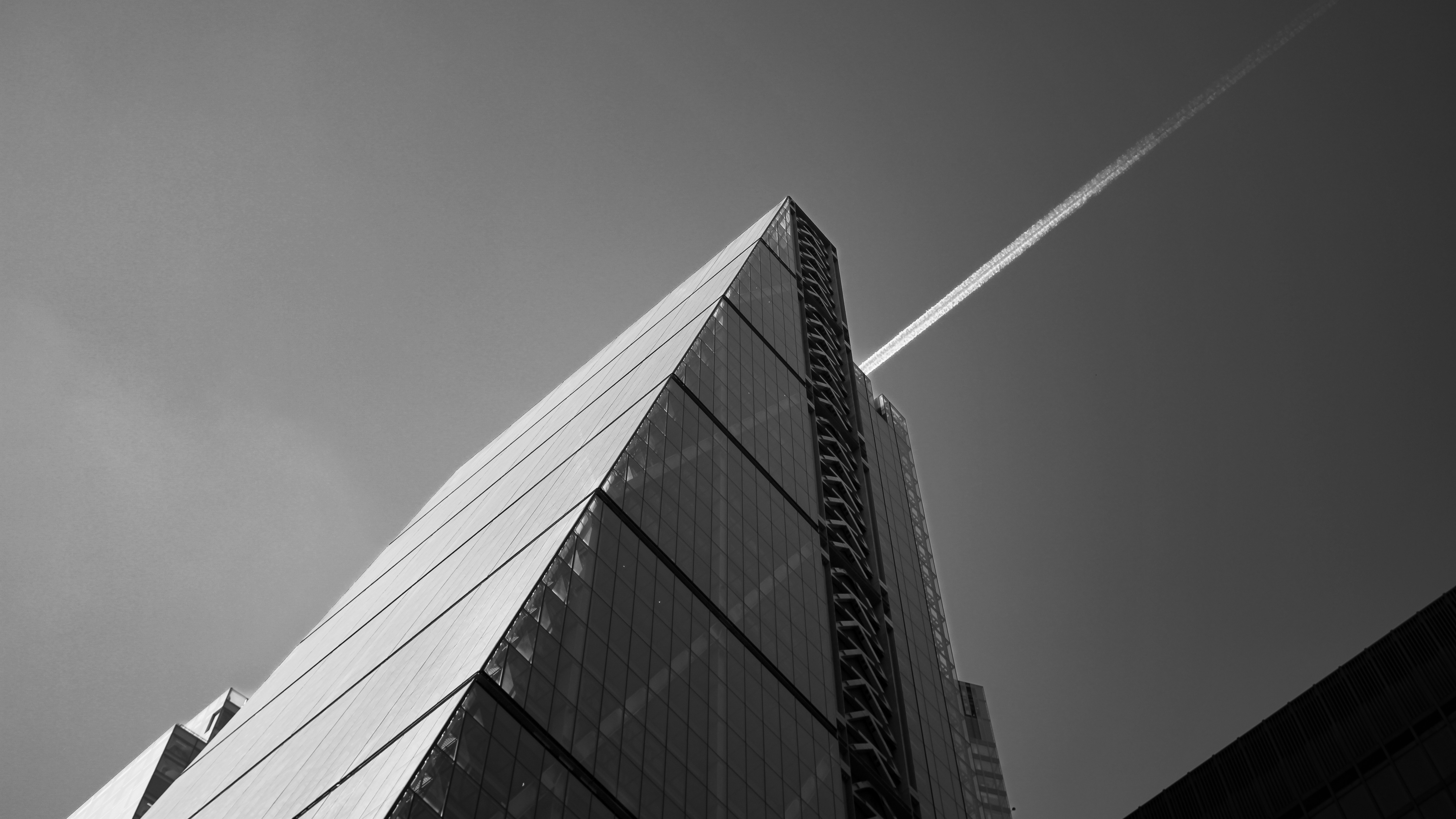 Modern skyscraper against a clear sky with contrail