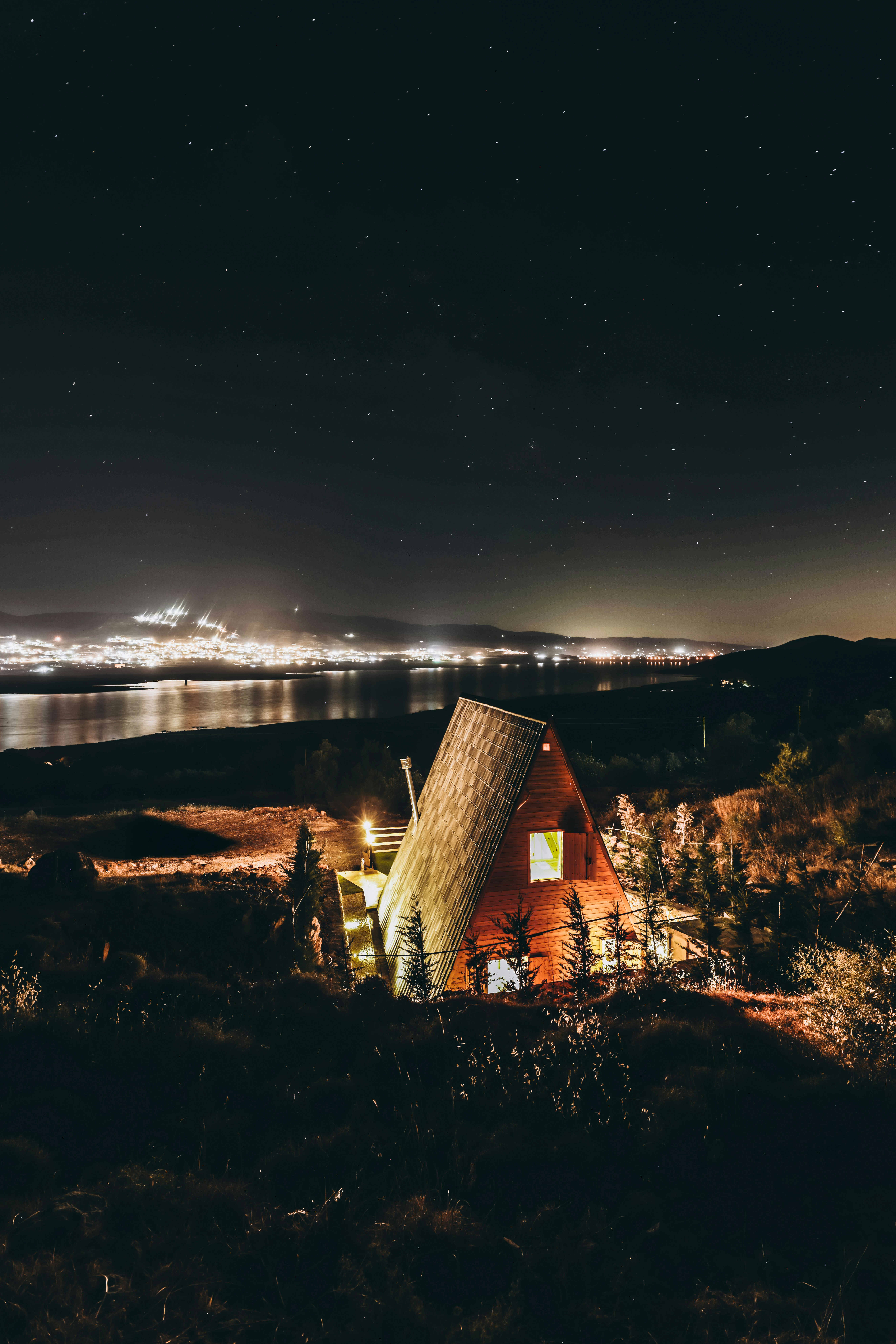 A-frame cabin at night with starry sky.