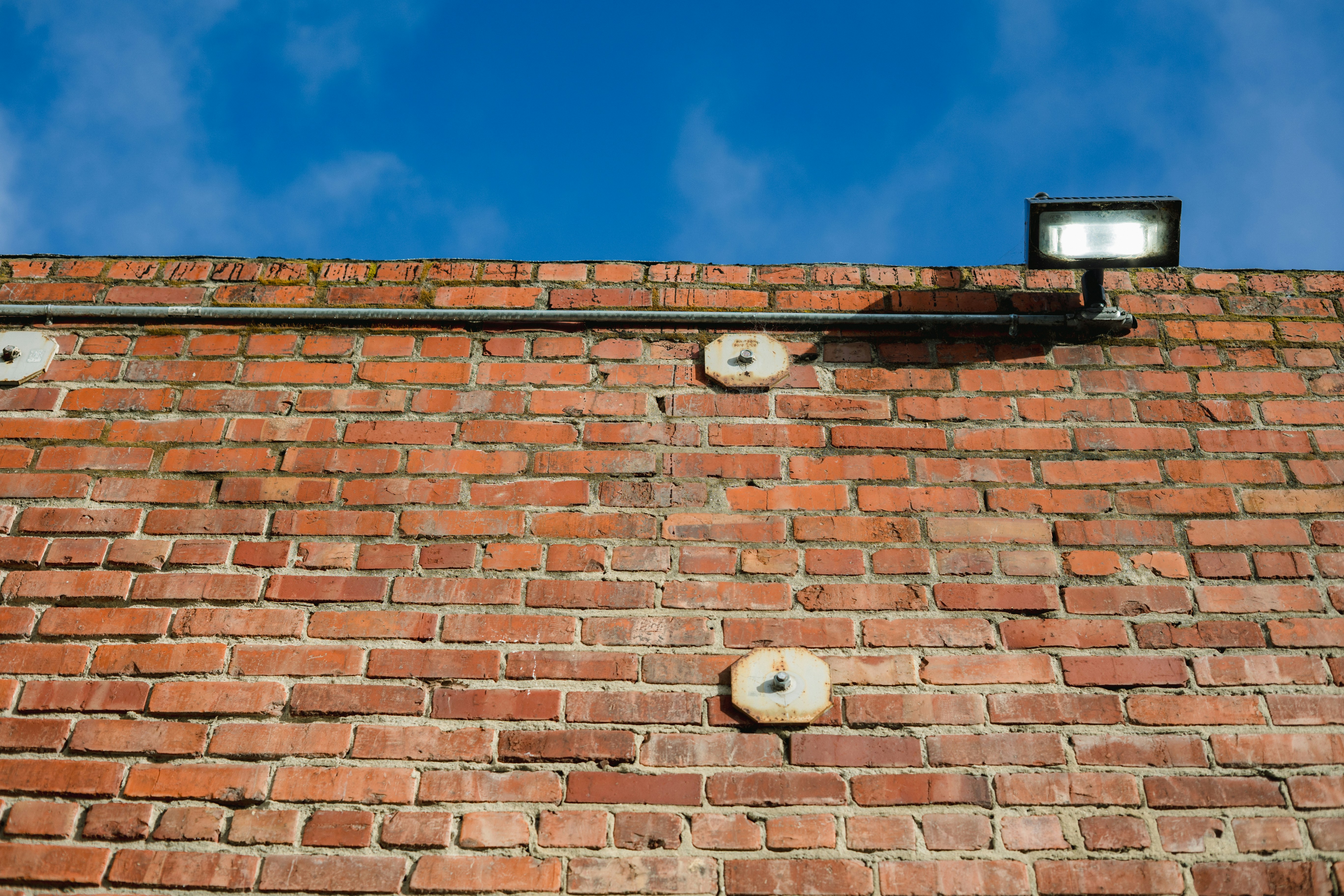 Brick wall with a security light under blue sky