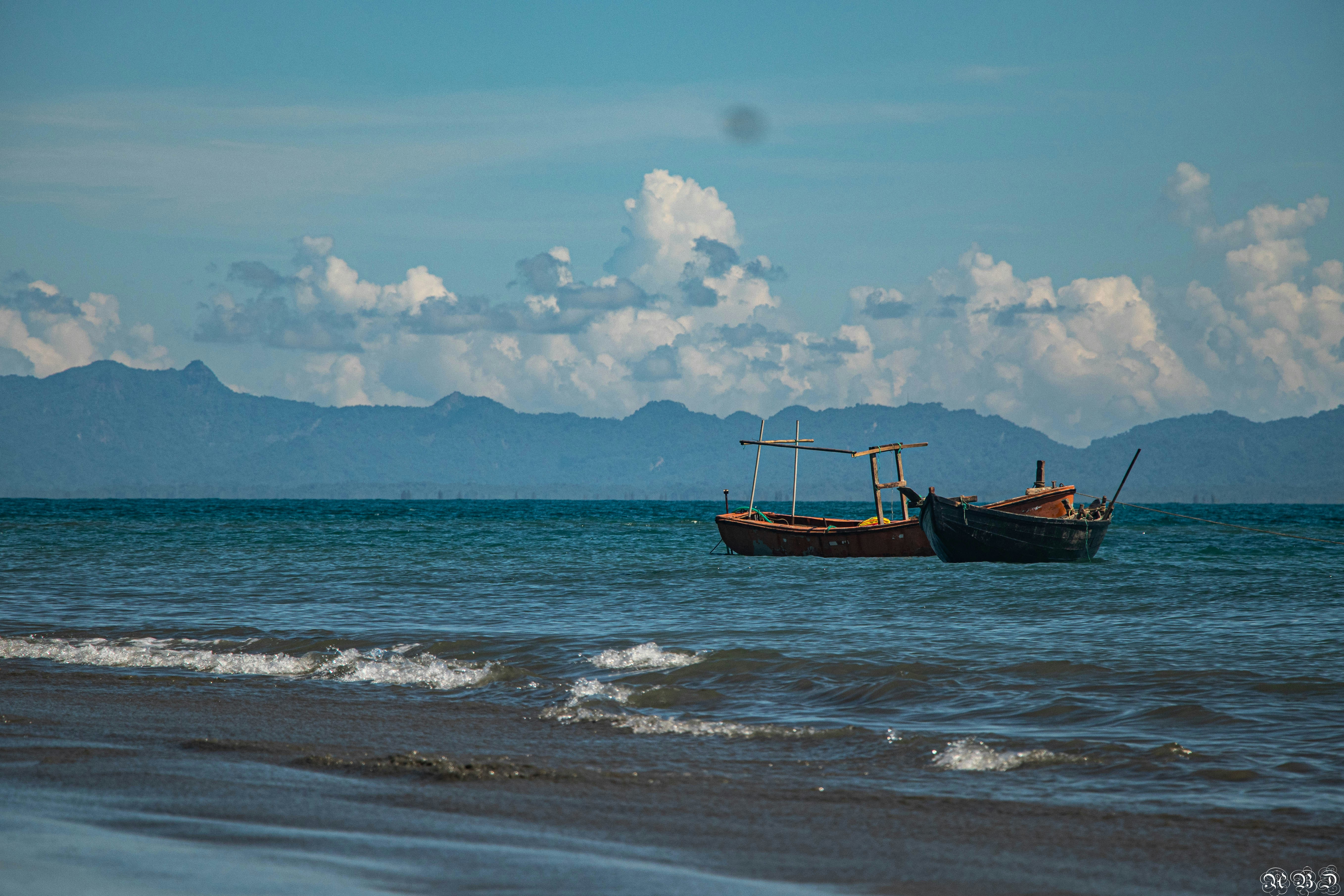 Sailing through the waves | Two boats float on the ocean near shore