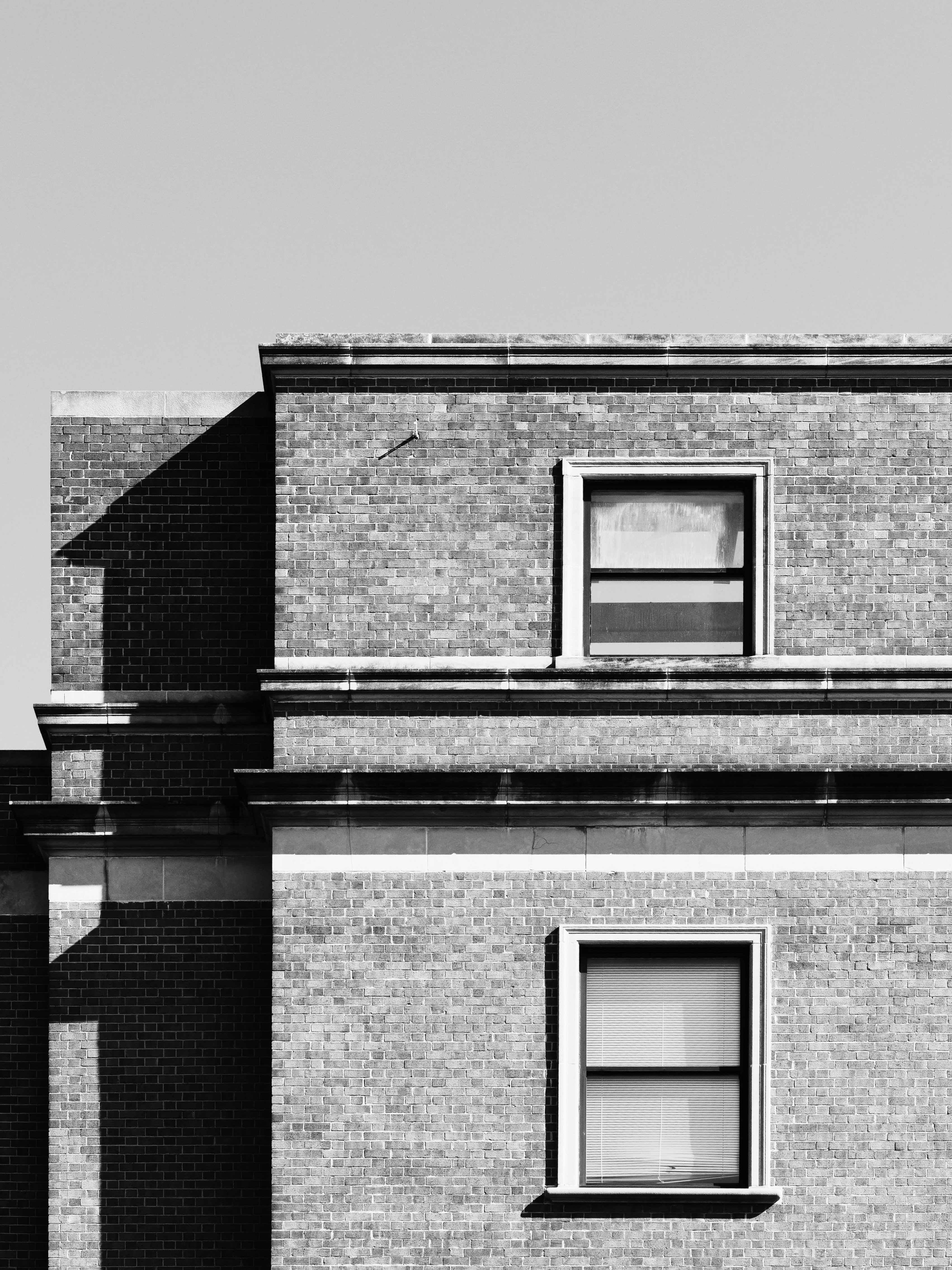 Monochrome depiction of a brick building's facade, highlighting the symmetry of windows and shadows.