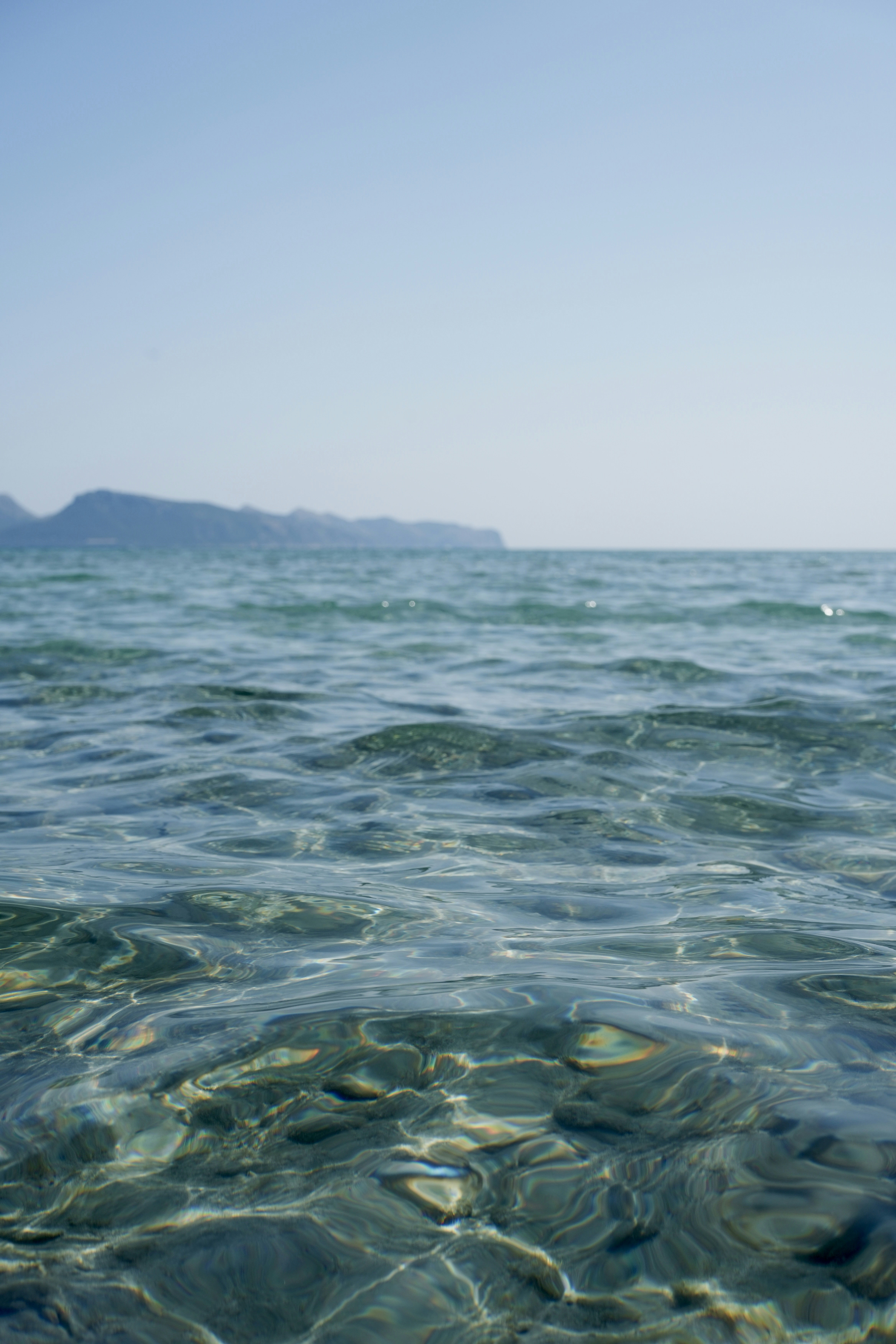 Clear ocean water with pebbles visible below