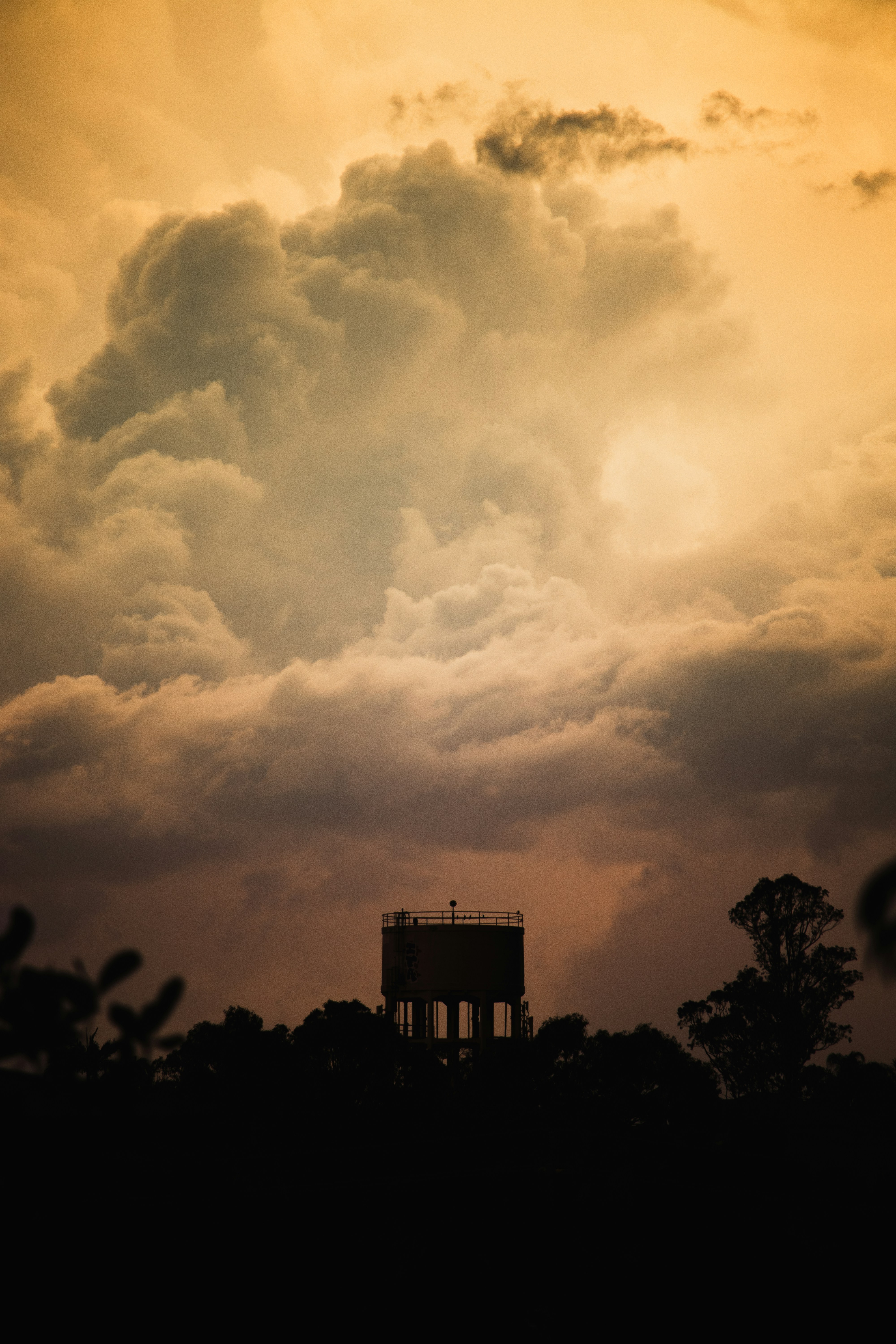 Silhouette of water tower against dramatic stormy clouds