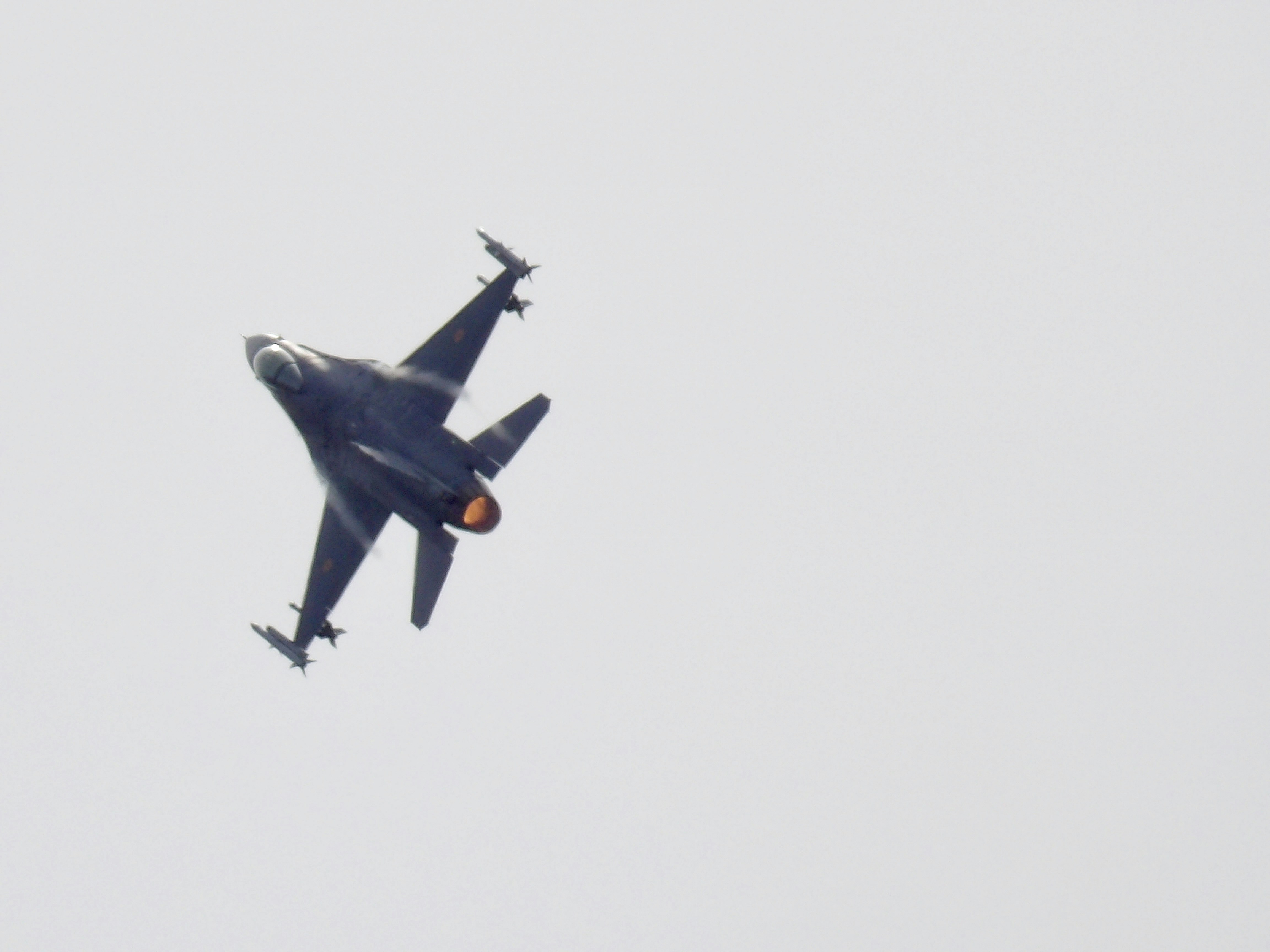 Fighter jet performing an aerial maneuver against a gray sky.