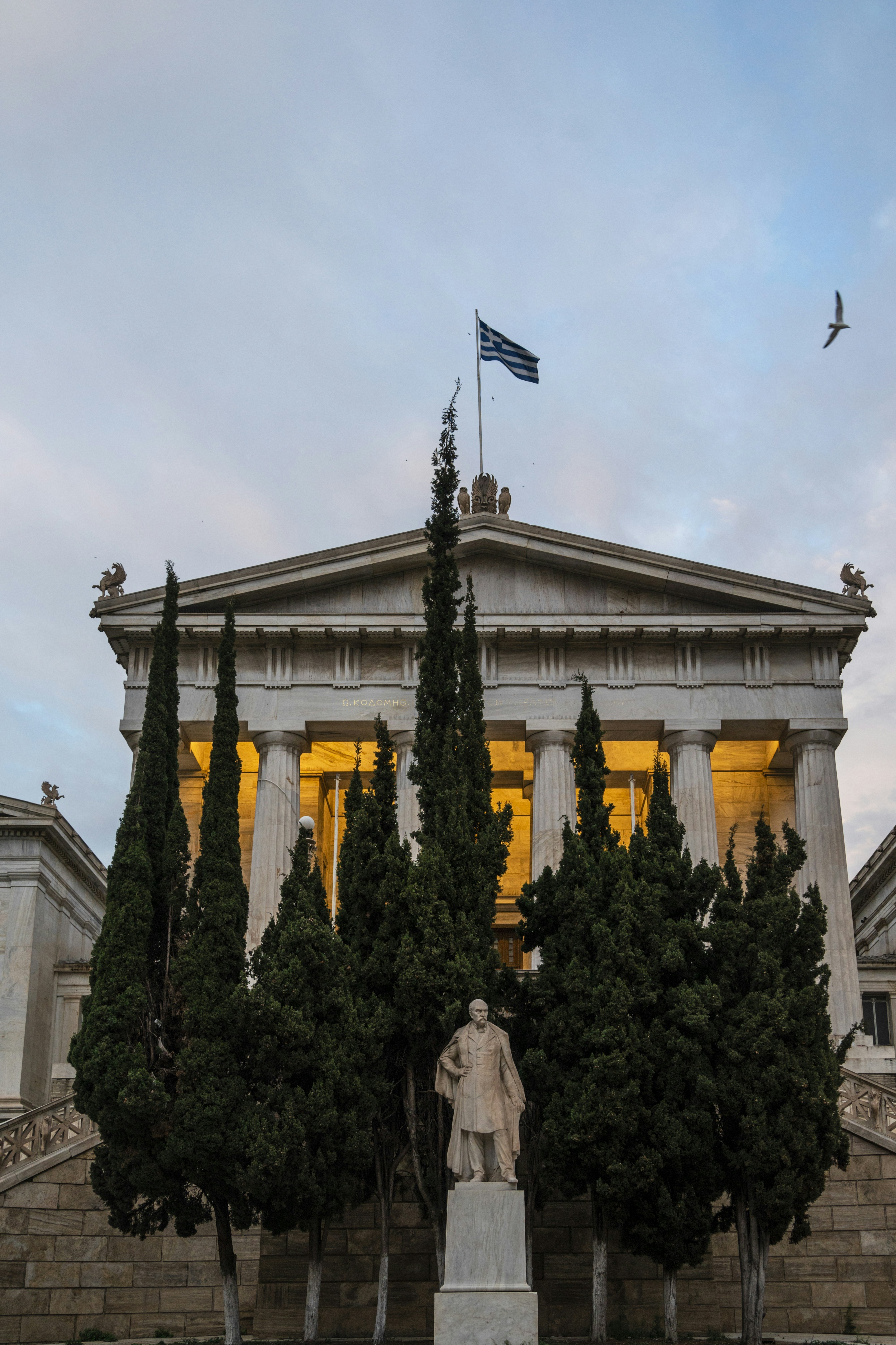 Neoclassical building with columns and statue outside.