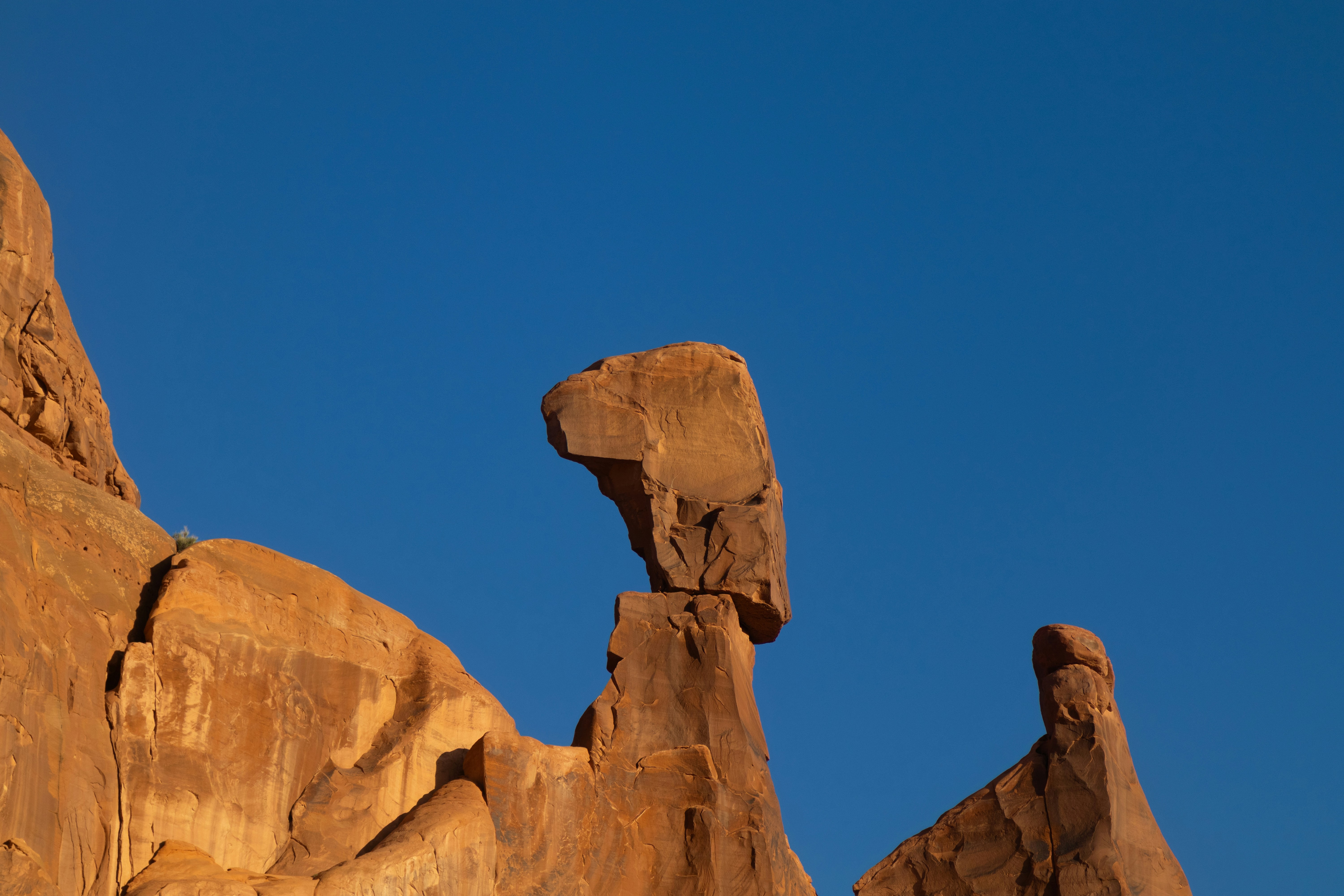 Balanced rock formation against a clear blue sky
