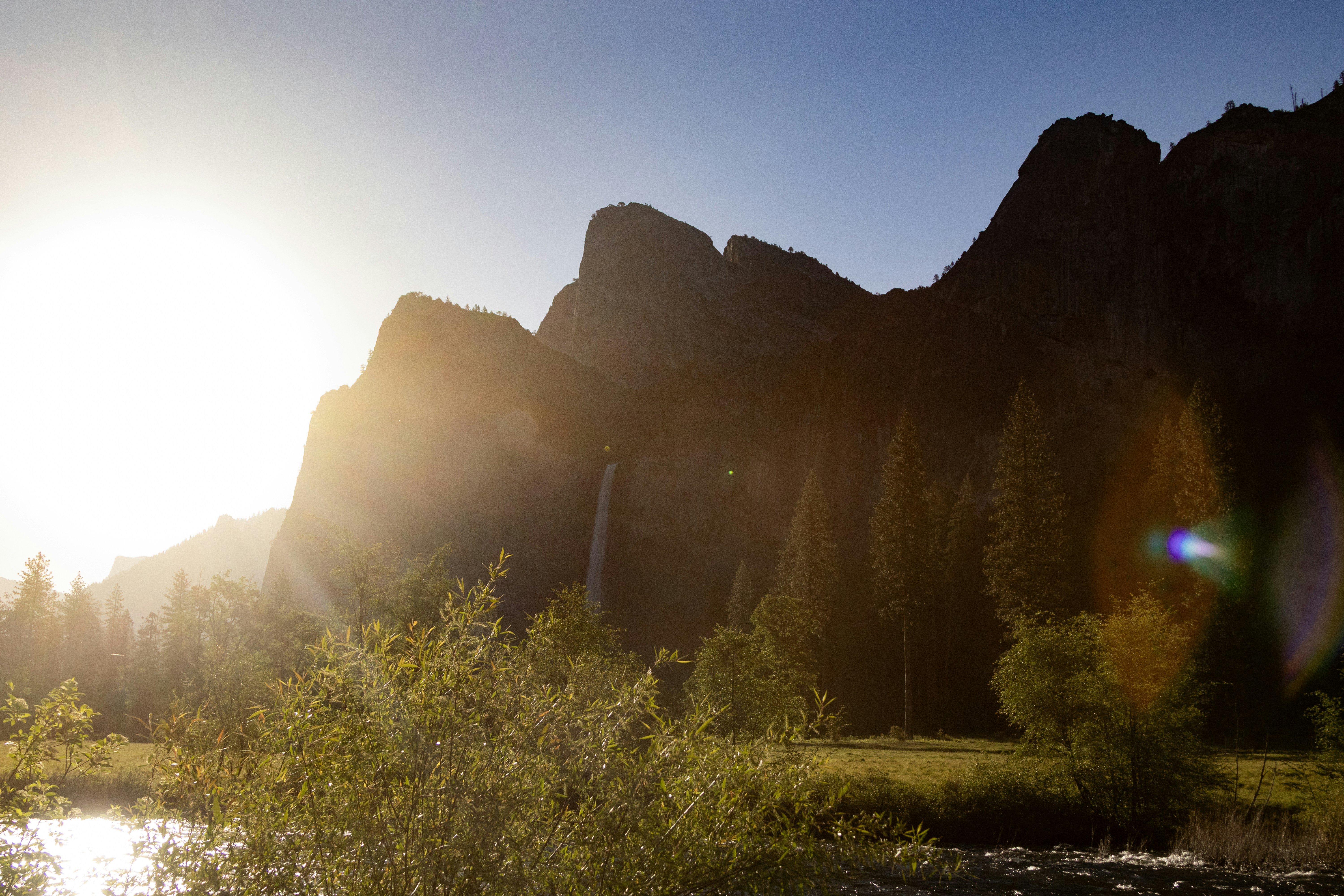 Sun setting behind majestic mountain peaks and forest