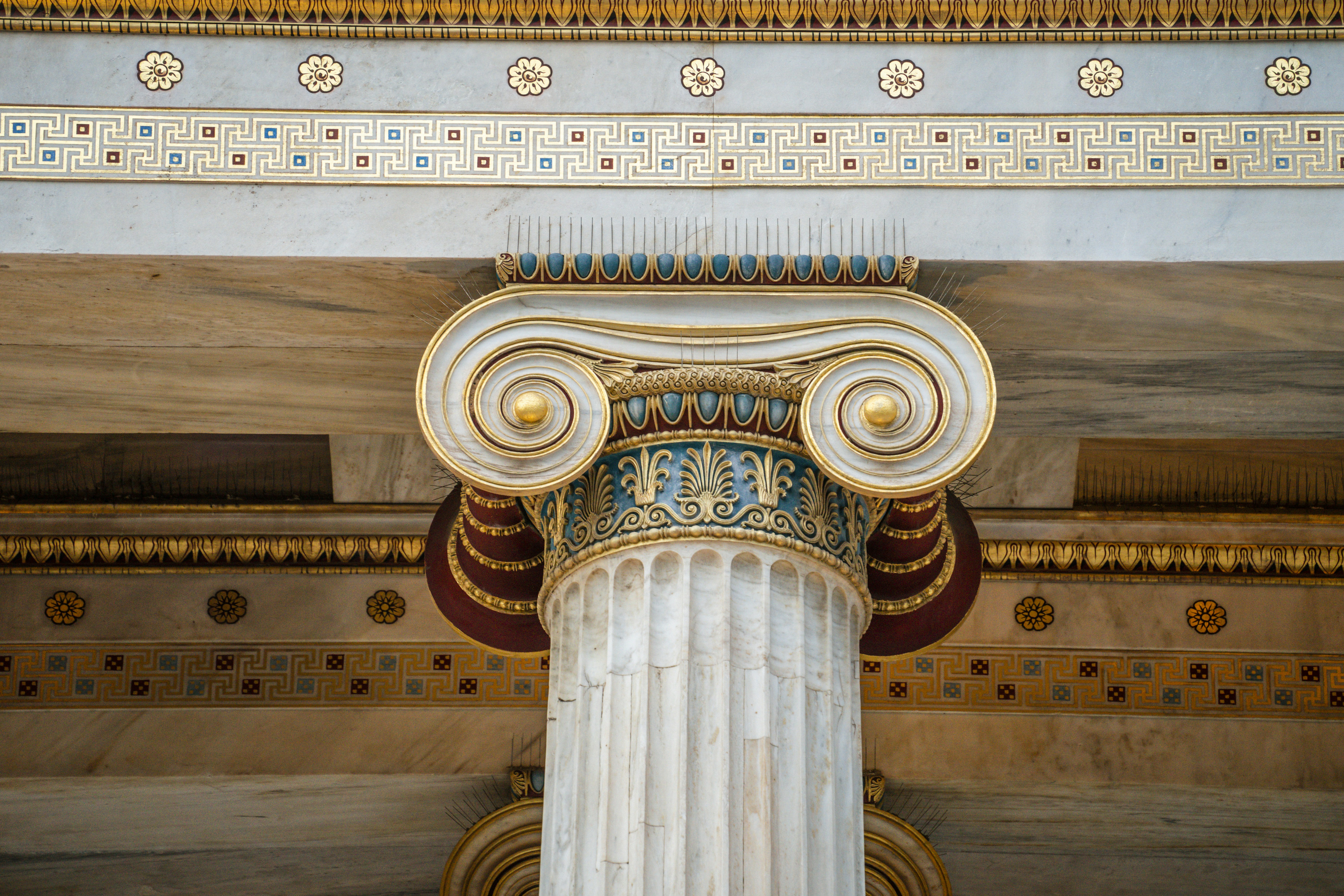 Close-up of an ornate ionic column capital with gold details.
