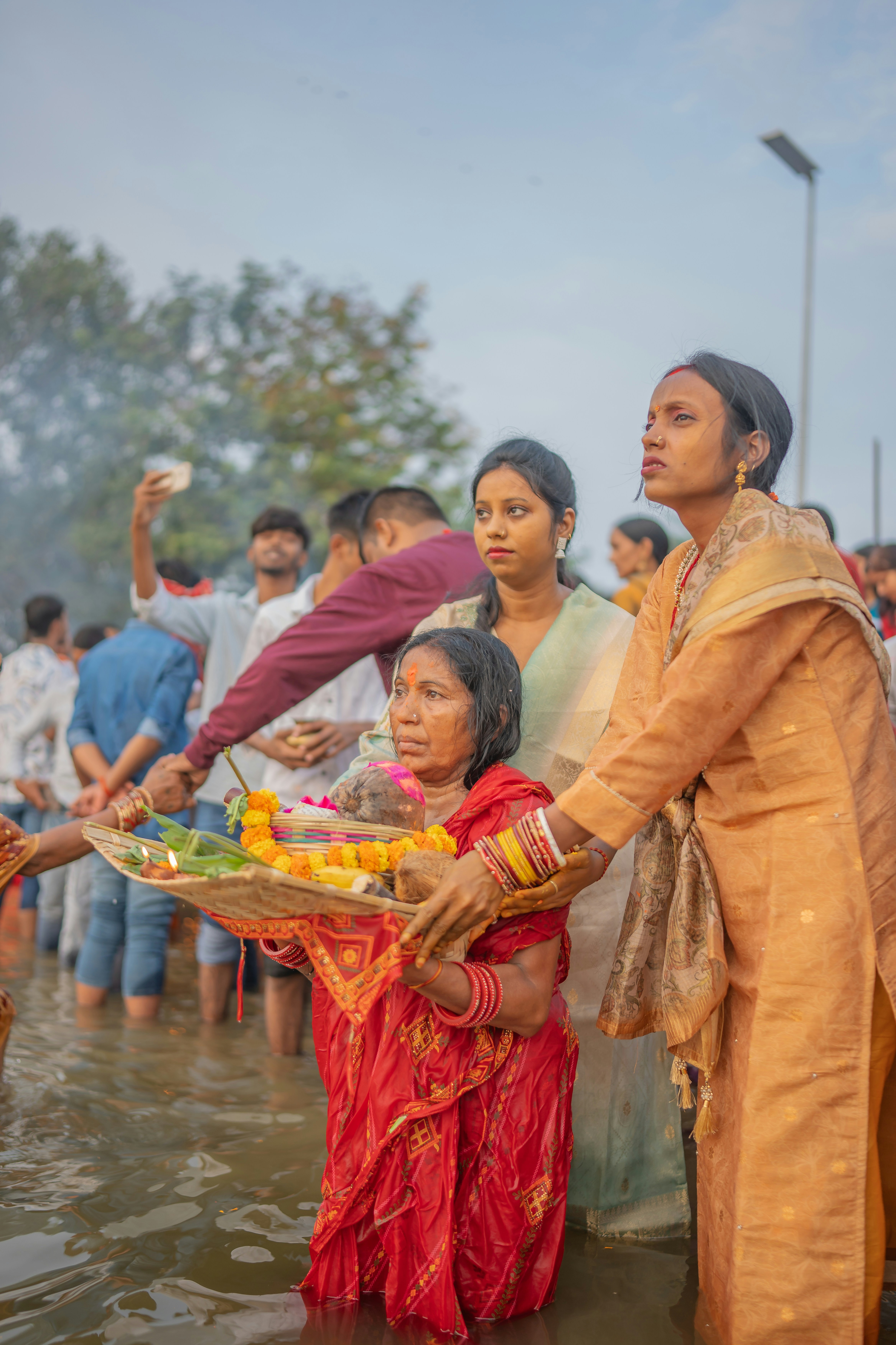 Red Sari Reverence: A Riverbank Offering in Blooming Color