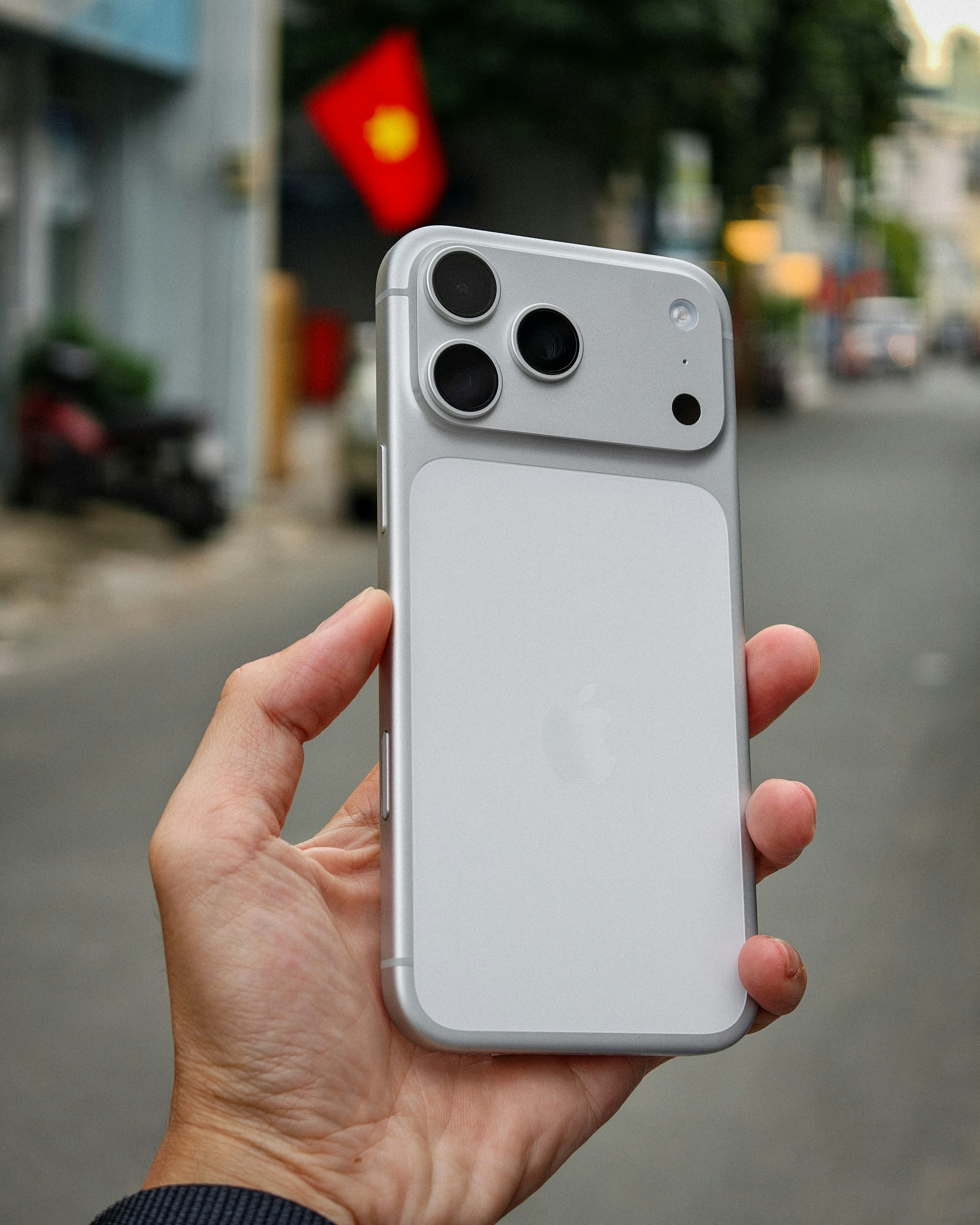 Apple iPhone 17 Pro Max Silver | Hand holding a silver smartphone with three cameras.