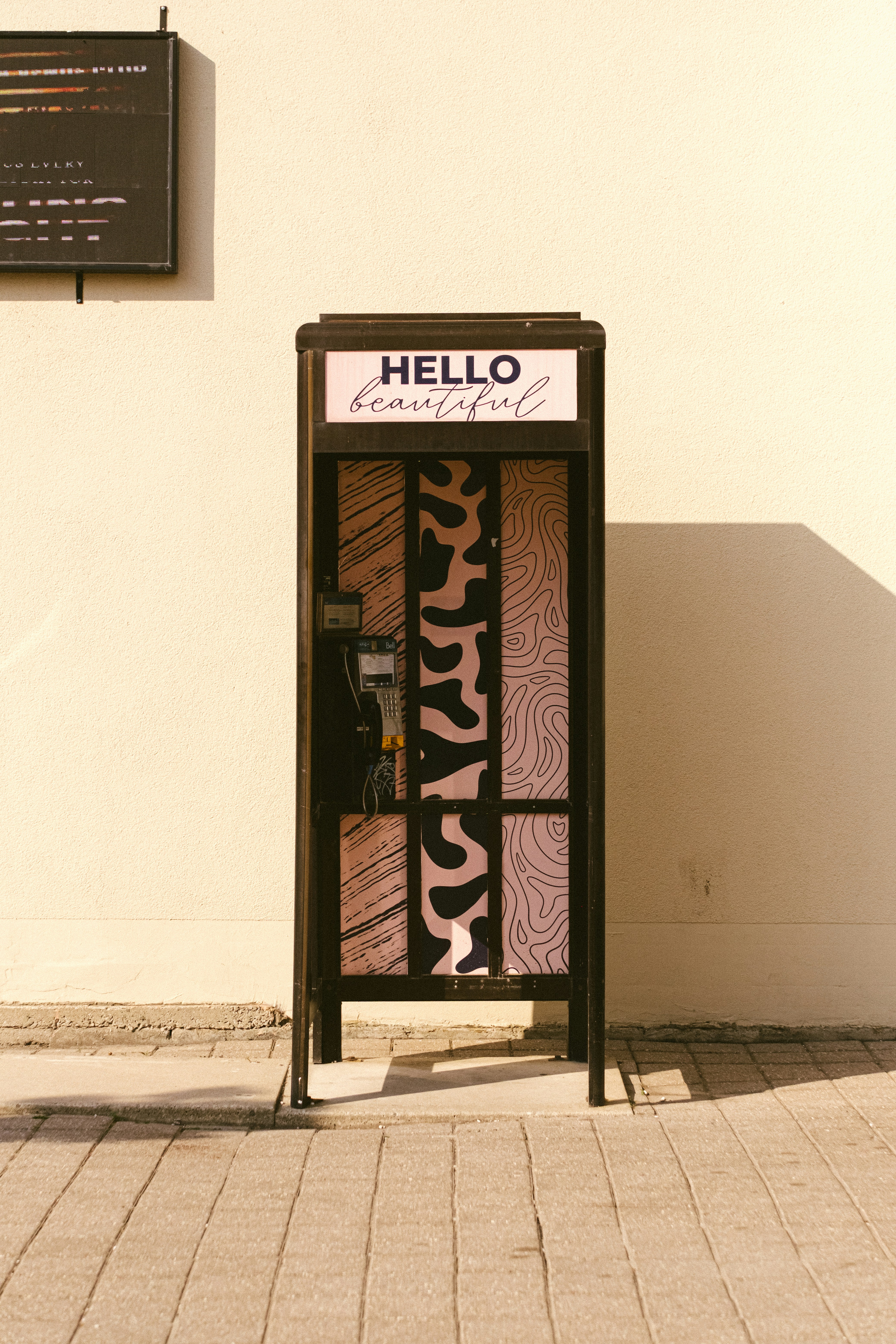 Vintage telephone booth with "hello beautiful" sign.