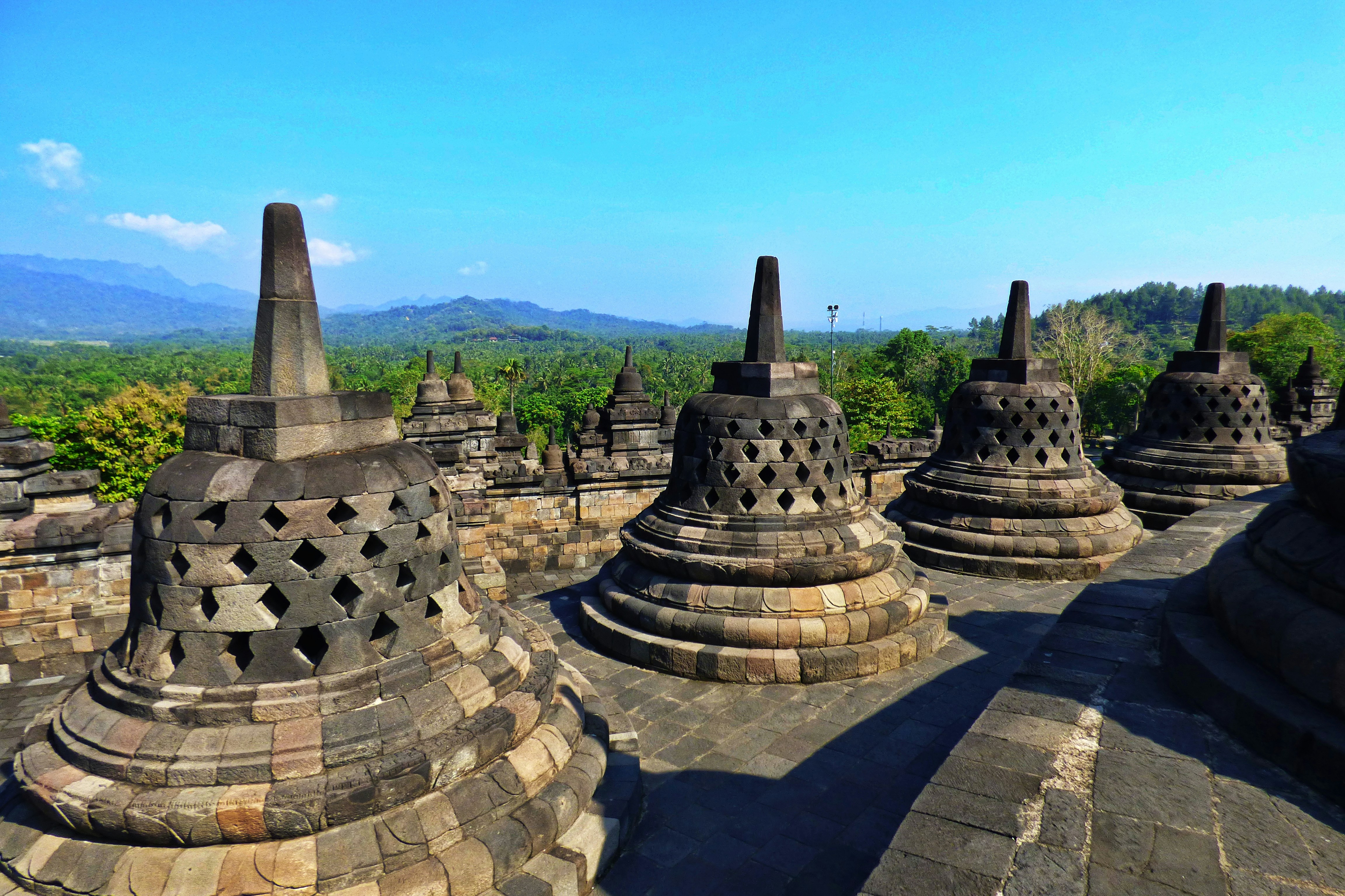 Ancient stupas at borobudur temple complex under blue sky
