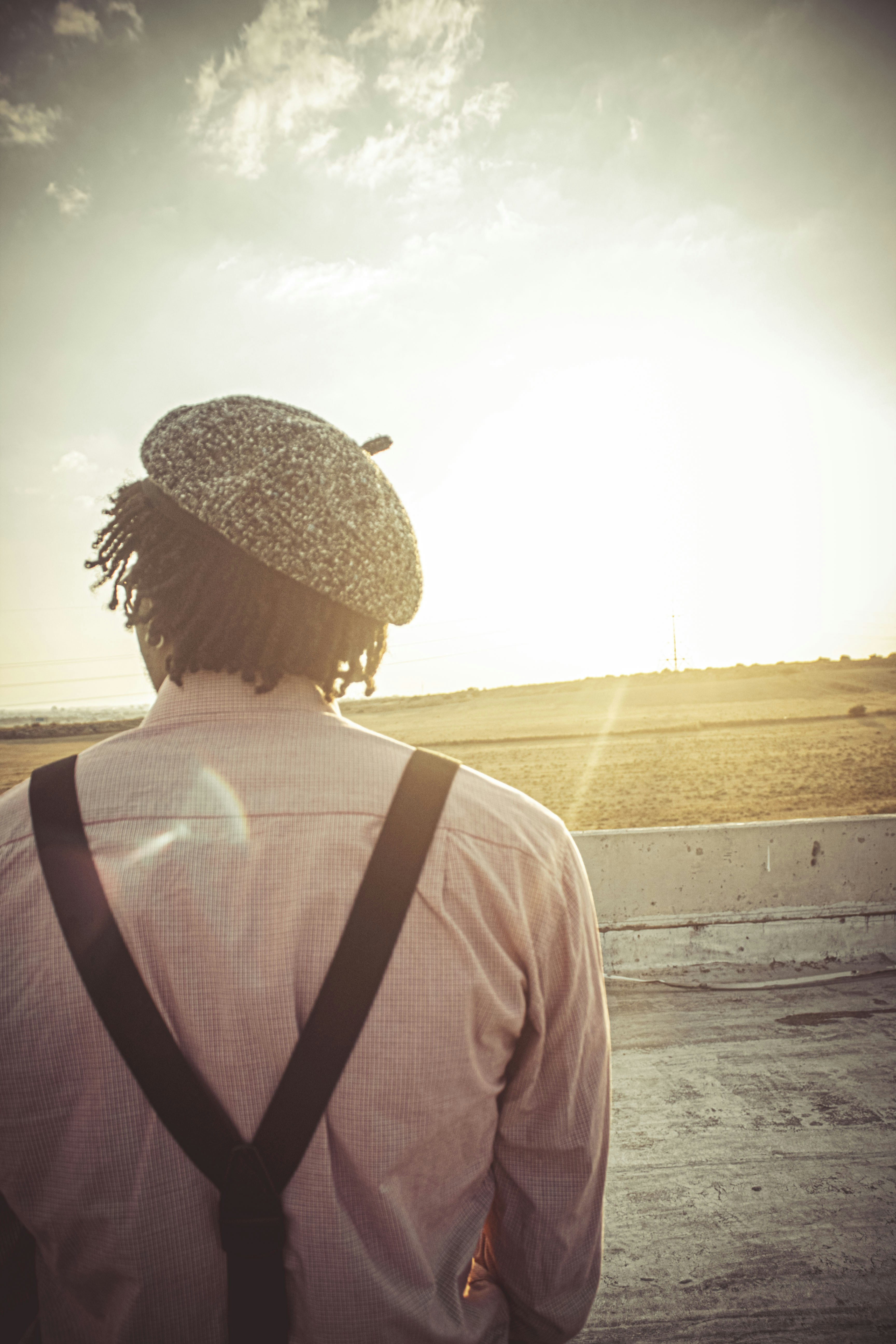 Person in hat and suspenders looking at sunset