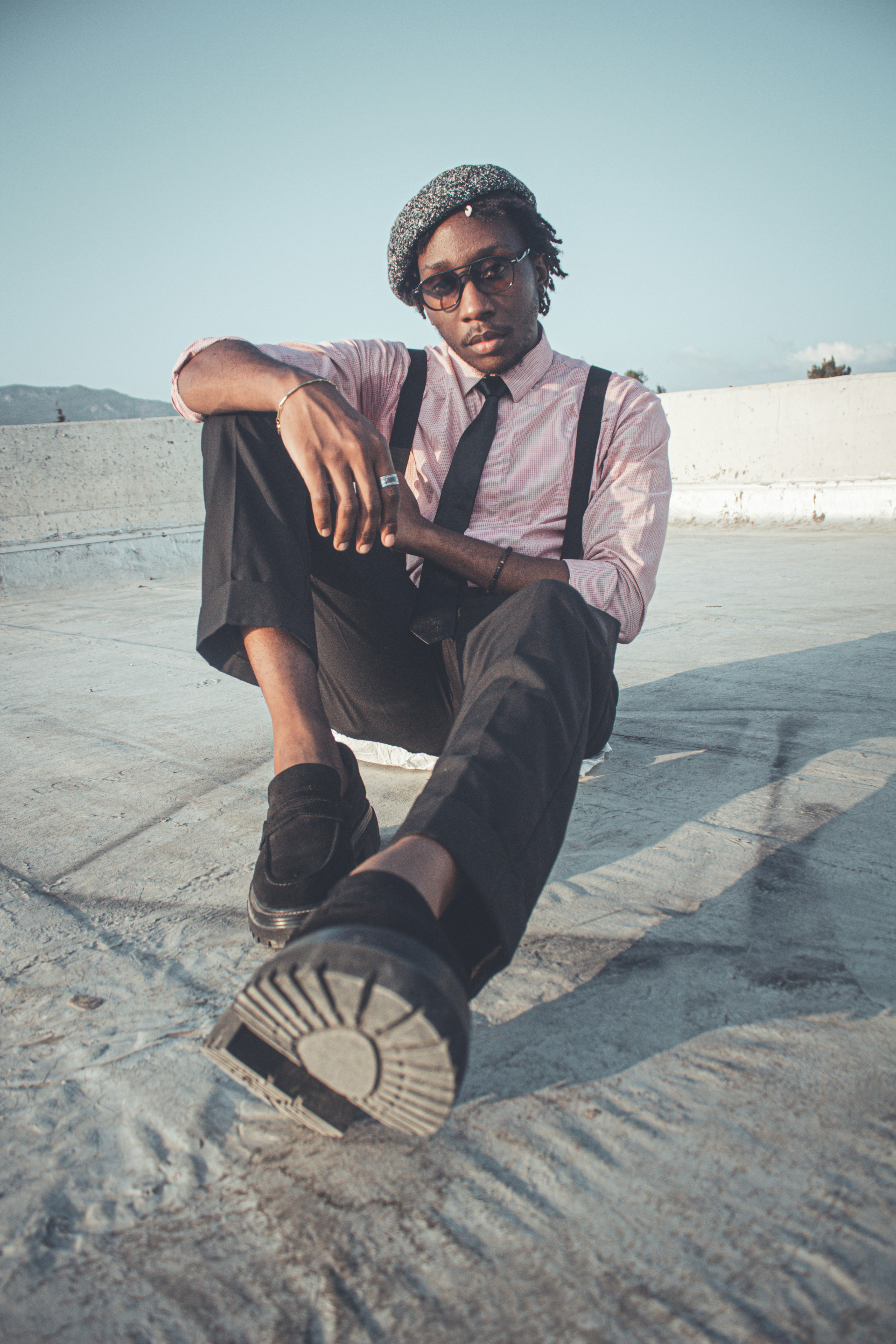 Stylishly dressed individual seated on a rooftop, showcasing a blend of contemporary fashion and urban backdrop.