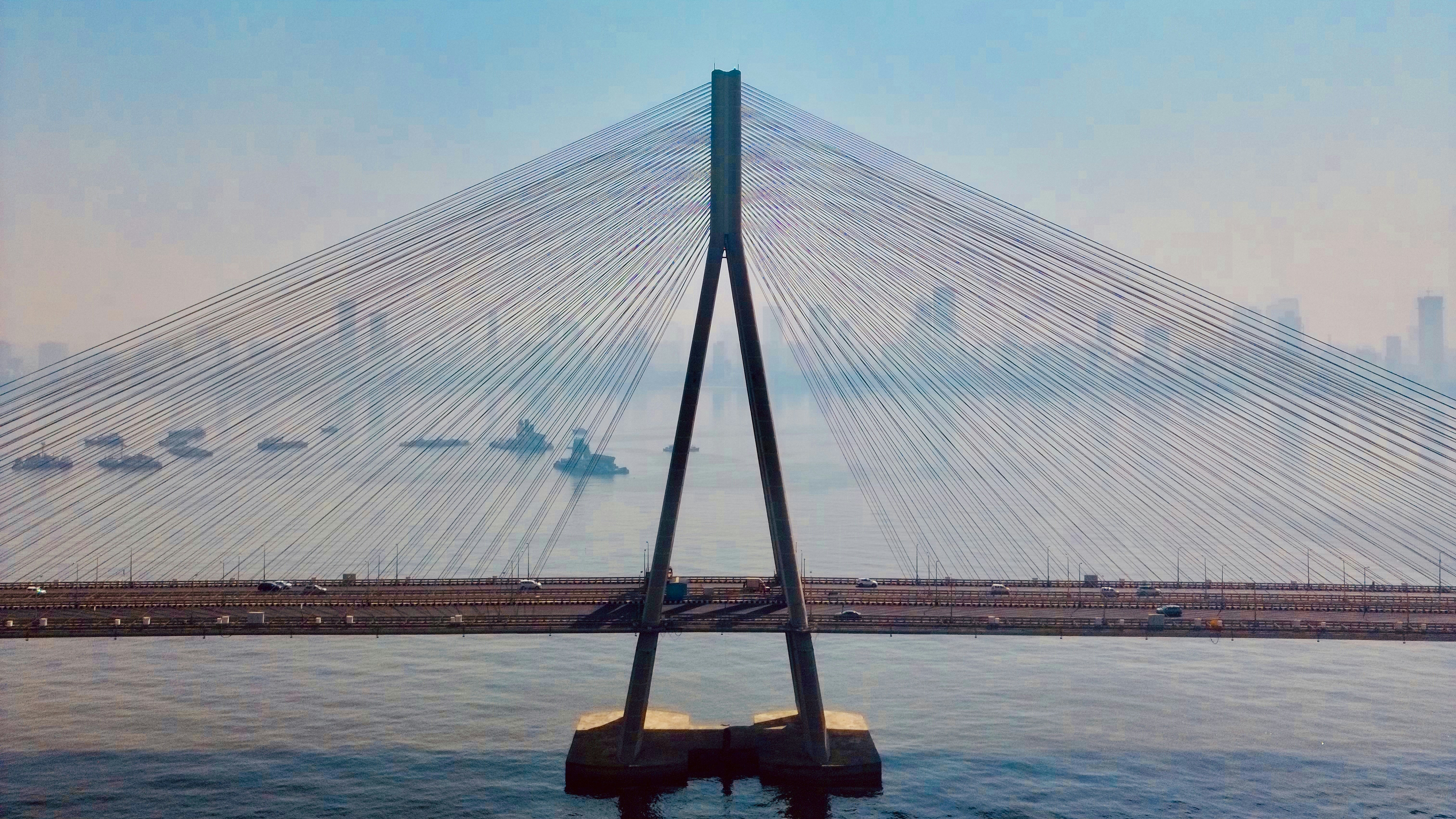 Bandra Worli Sea Link Bridge, with the silhouette of the Mumbai Skyline standing tall in the background | Cable-stayed bridge over water with cityscape background