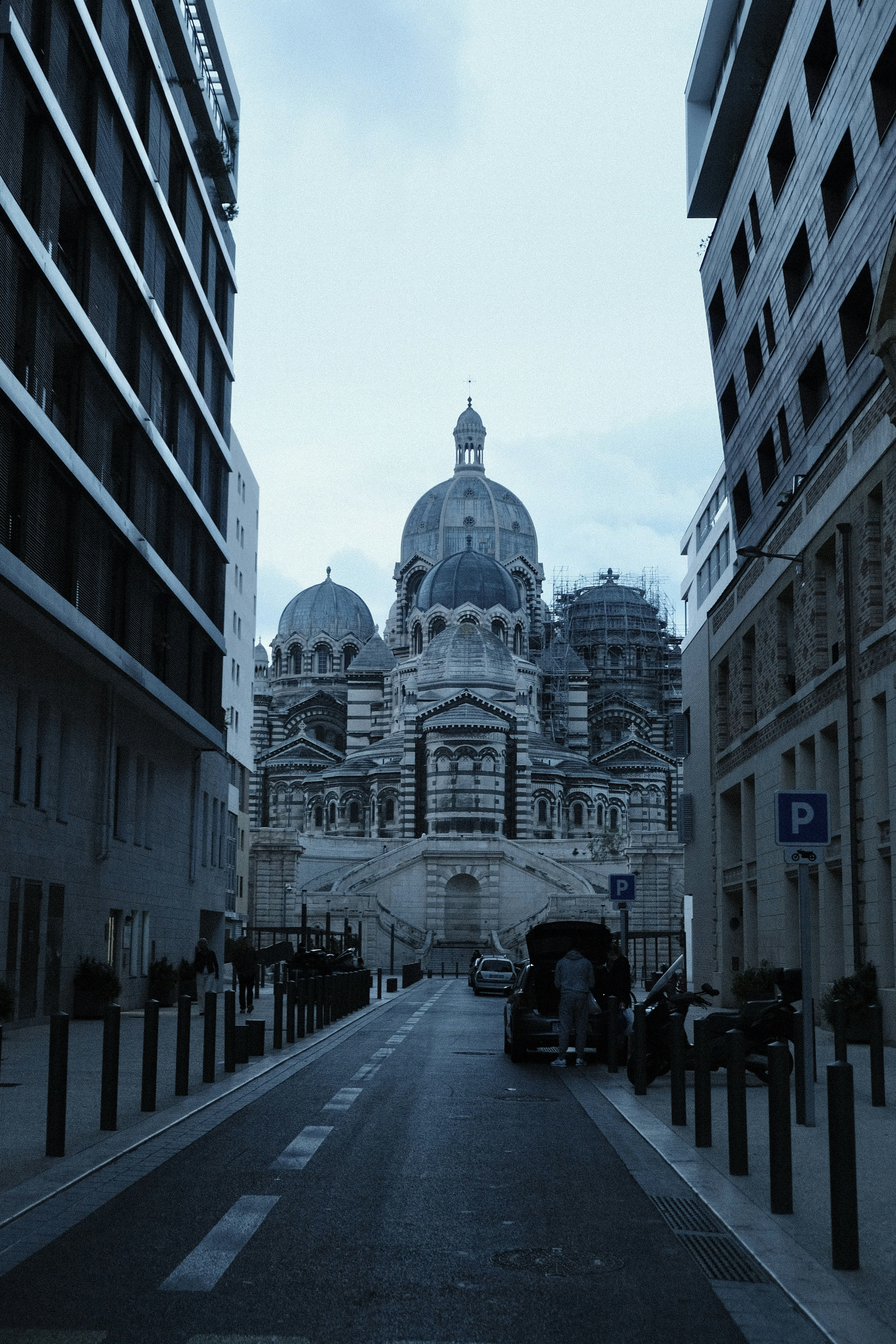 Historic cathedral framed by modern buildings, showcasing a blend of architectural styles. The scene captures the contrast between old and new urban landscapes.