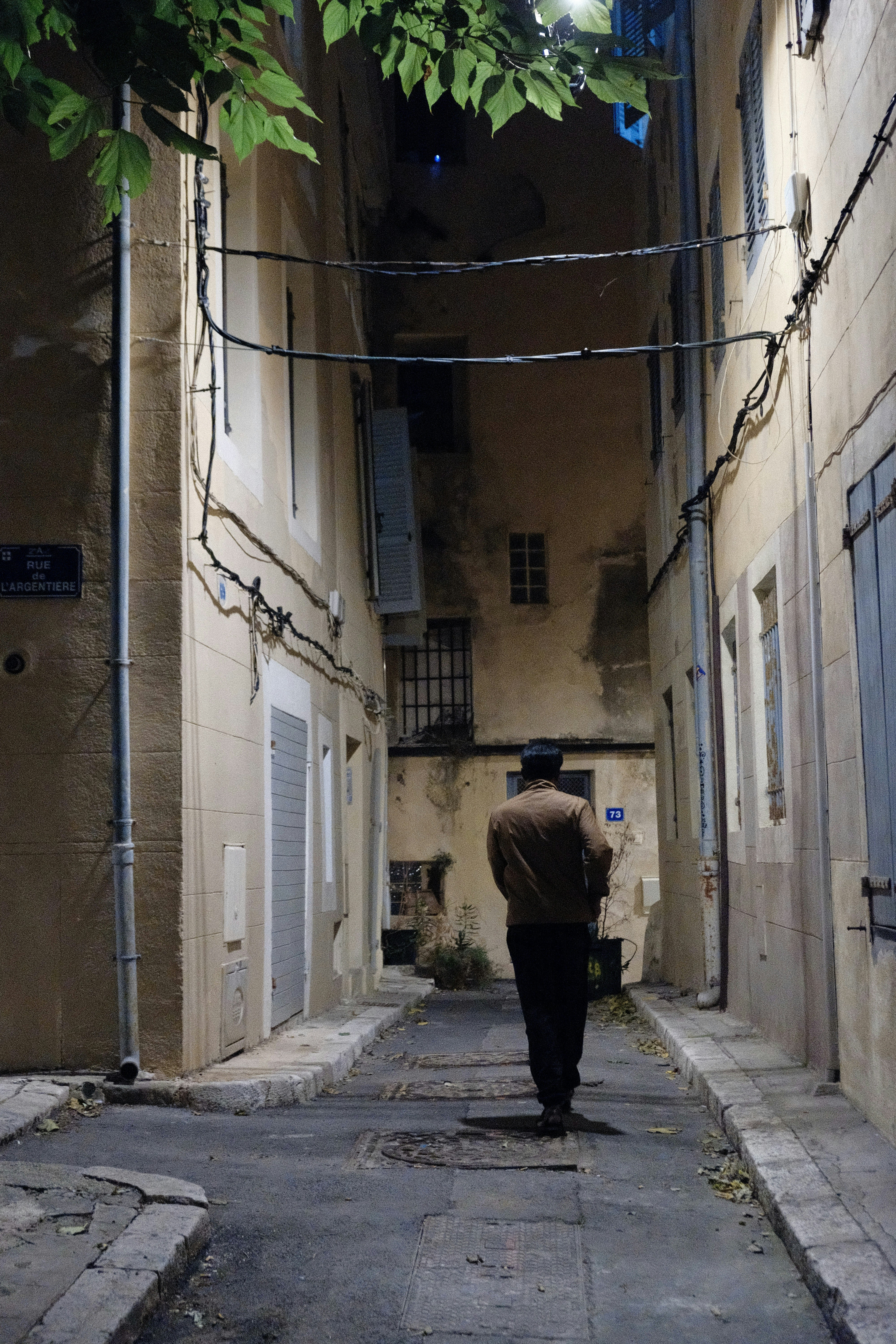 Man walks down a narrow european street at night.