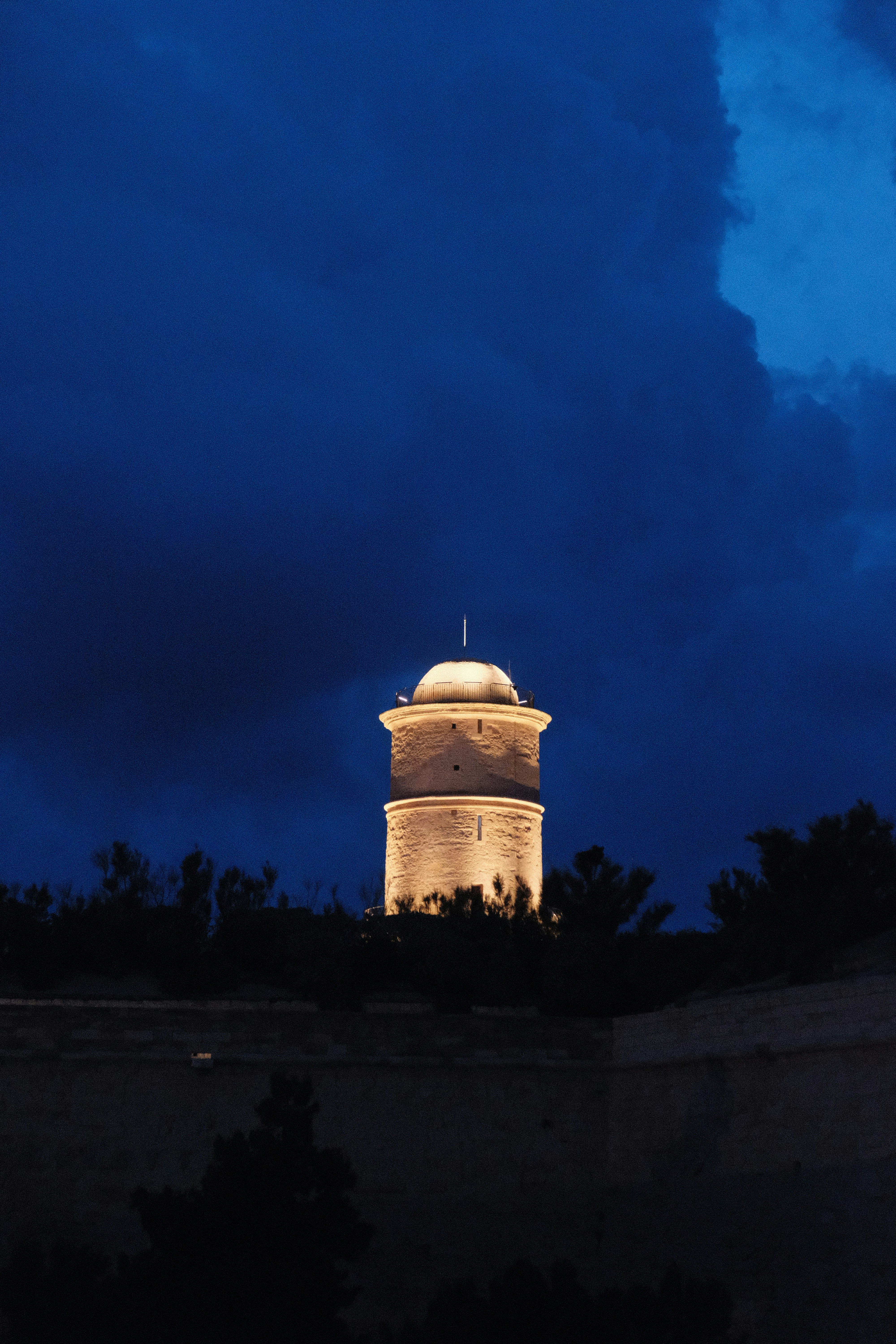Illuminated tower against a dark blue night sky