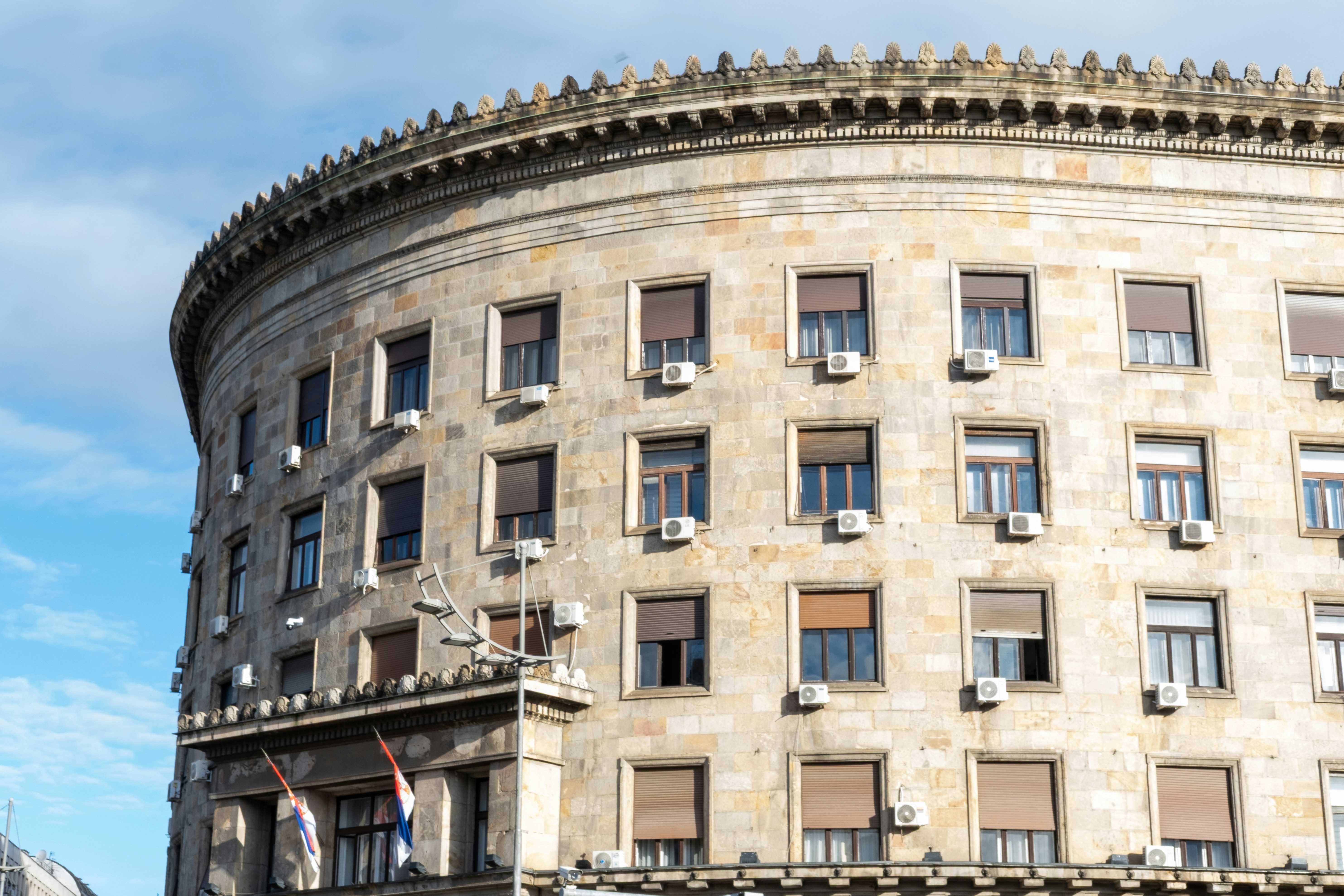 Historic building with a rounded facade and multiple air conditioning units, showcasing architectural details against a clear sky.