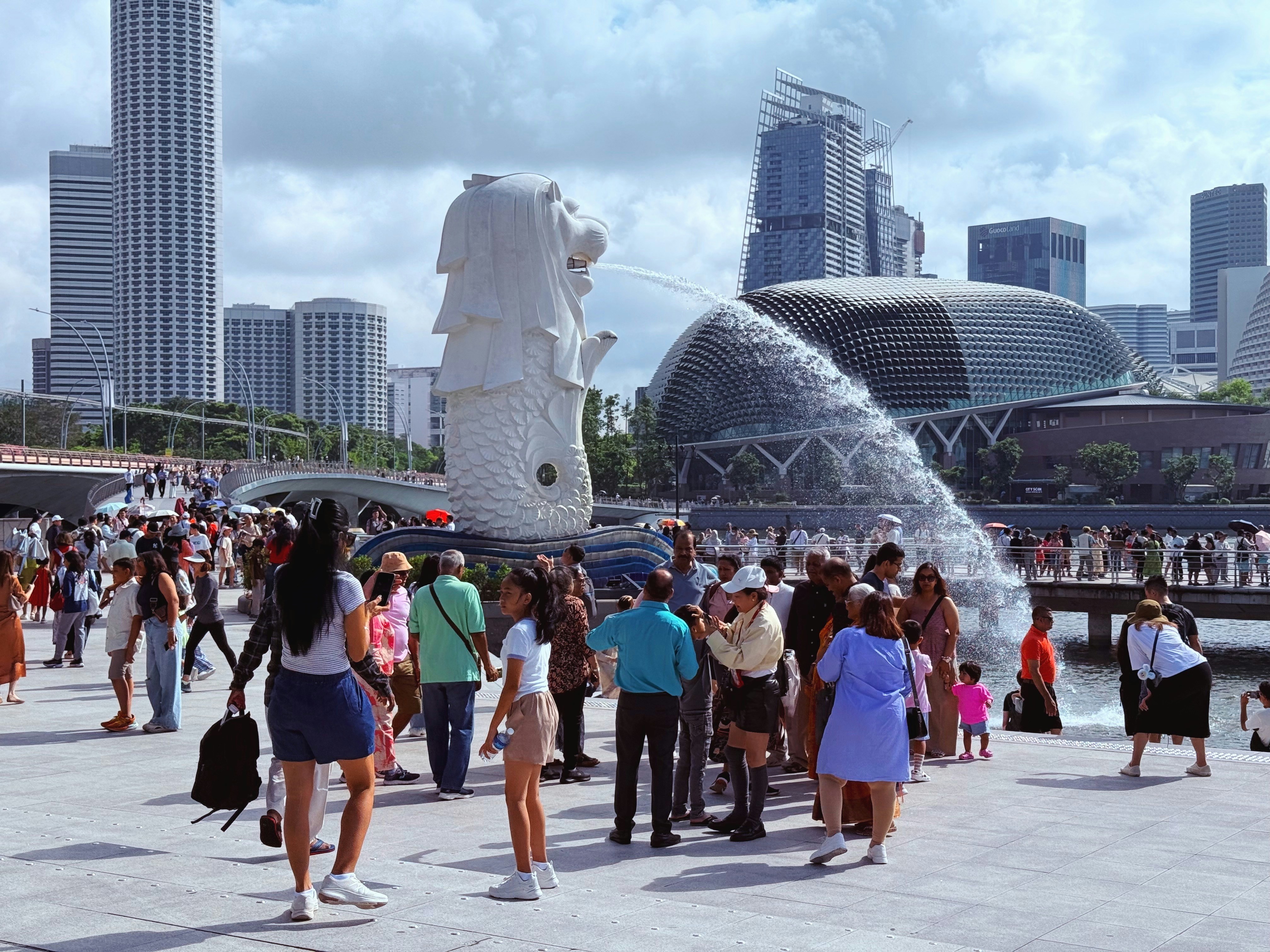 Visiting the Merlion in Singapore. | Crowds gather around the merlion statue with city skyline.