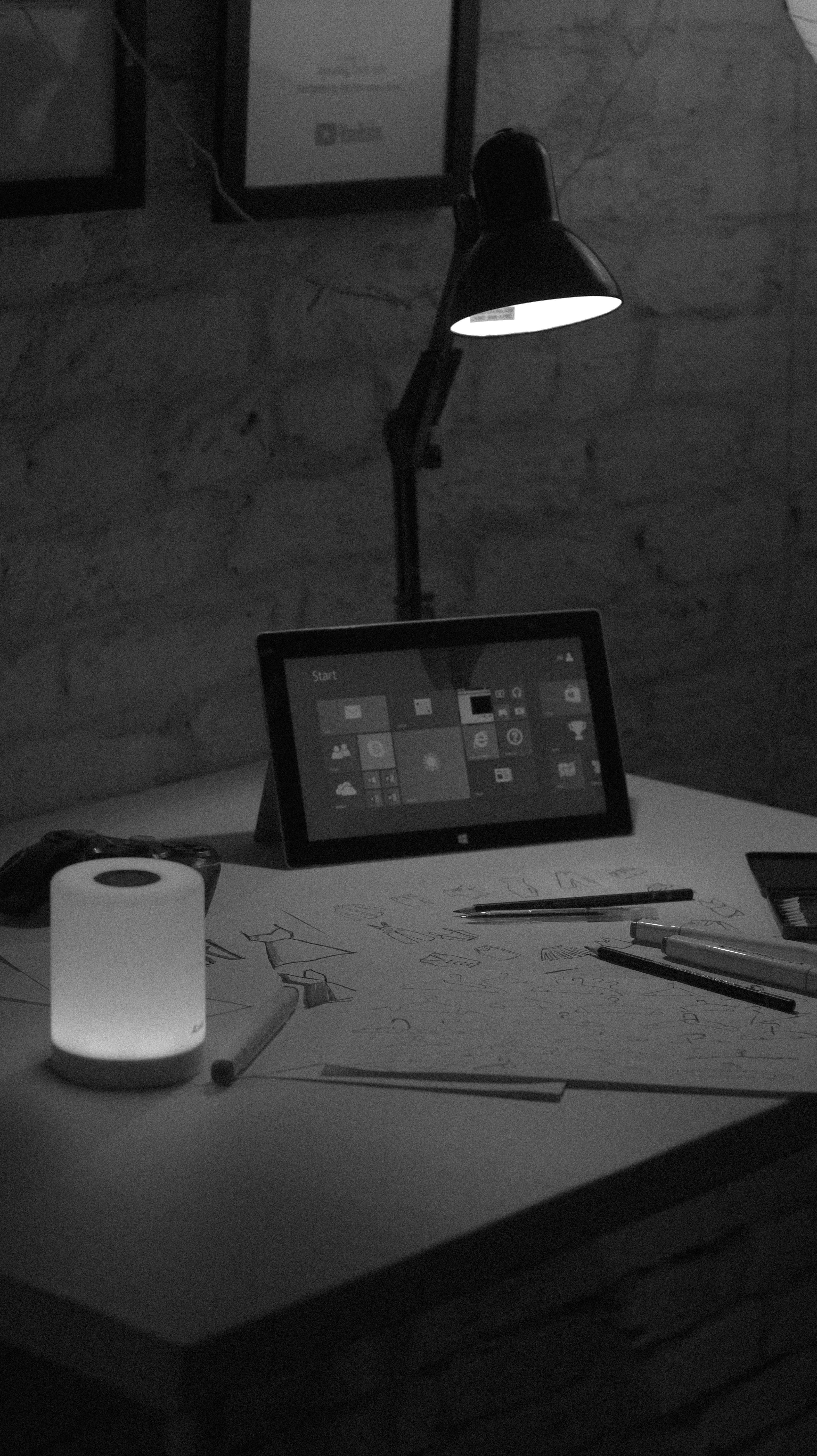 Desk with tablet, lamp, and drawing supplies.