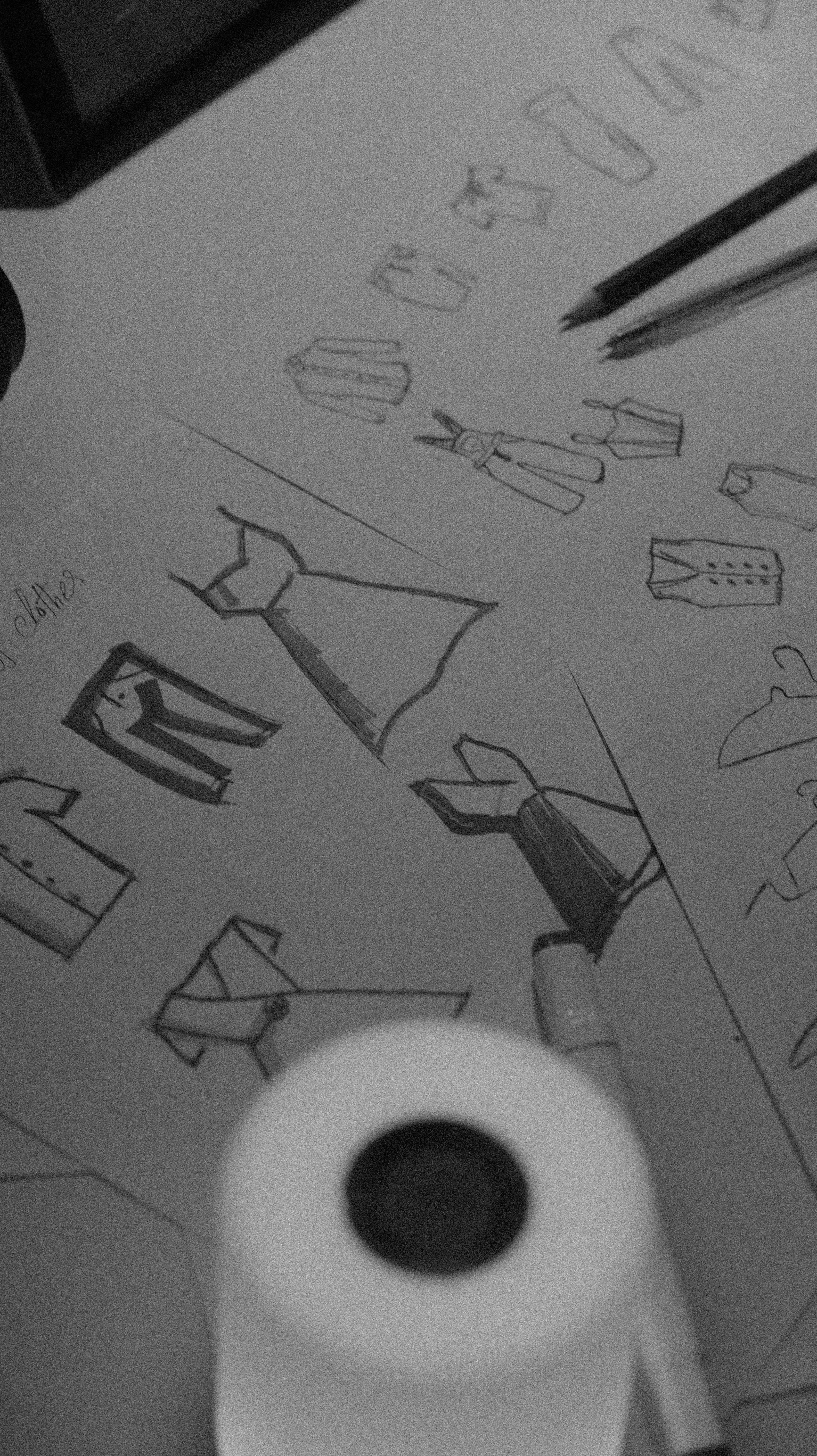 Fashion sketches featuring various clothing designs on a workspace, accompanied by pencils and a roll of tape. 