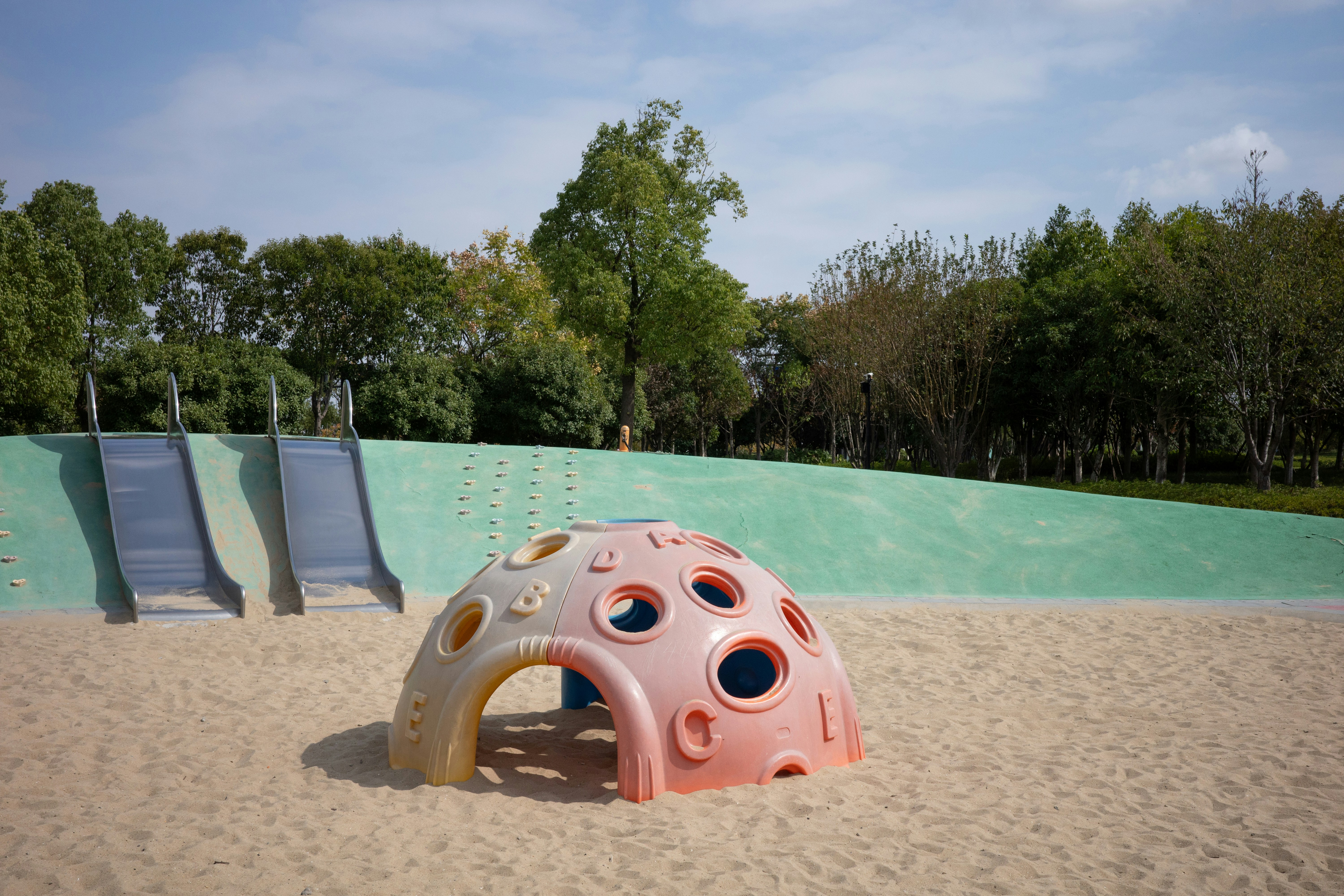 Playground with slides and dome climber in sand