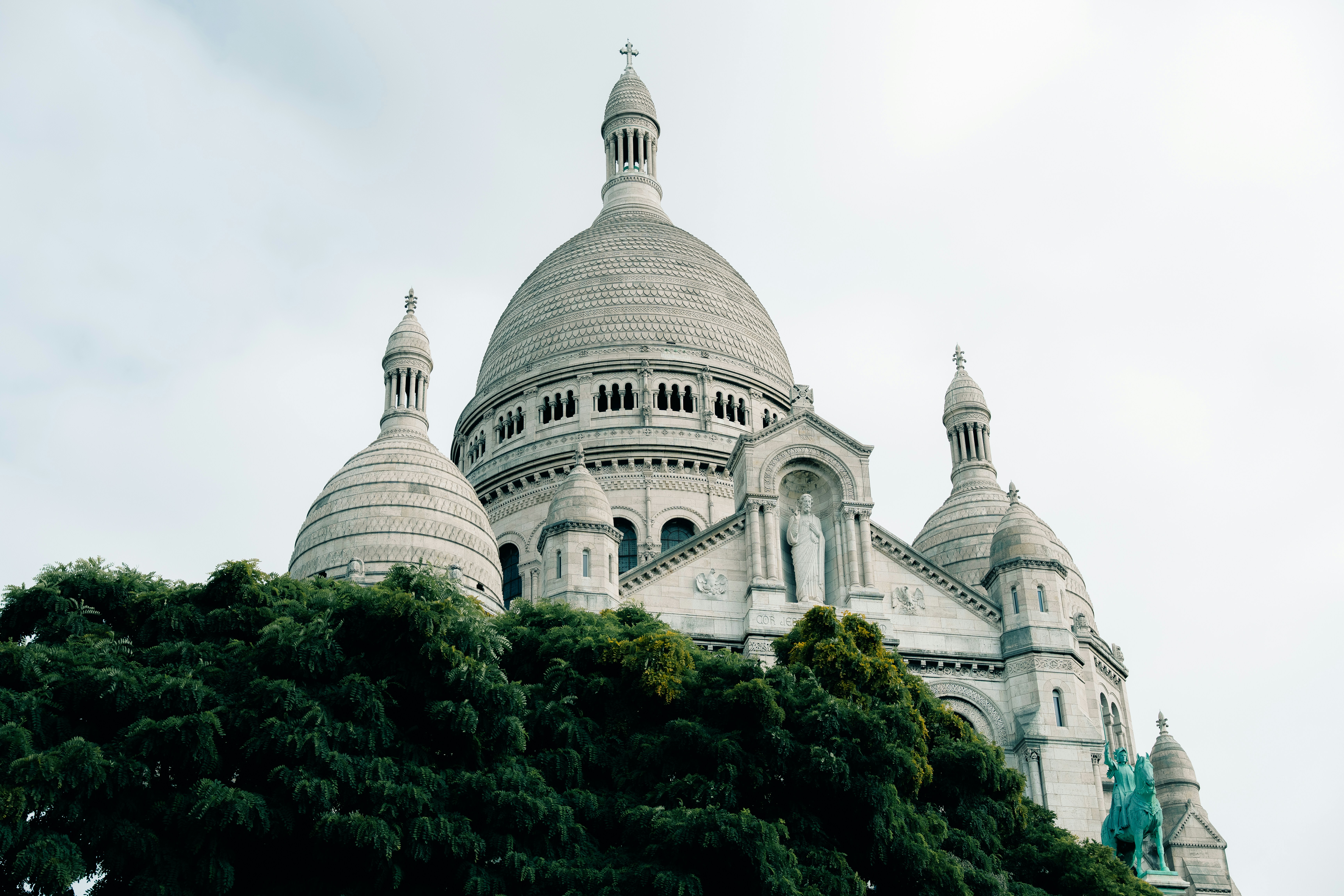 White domed basilica behind lush green trees