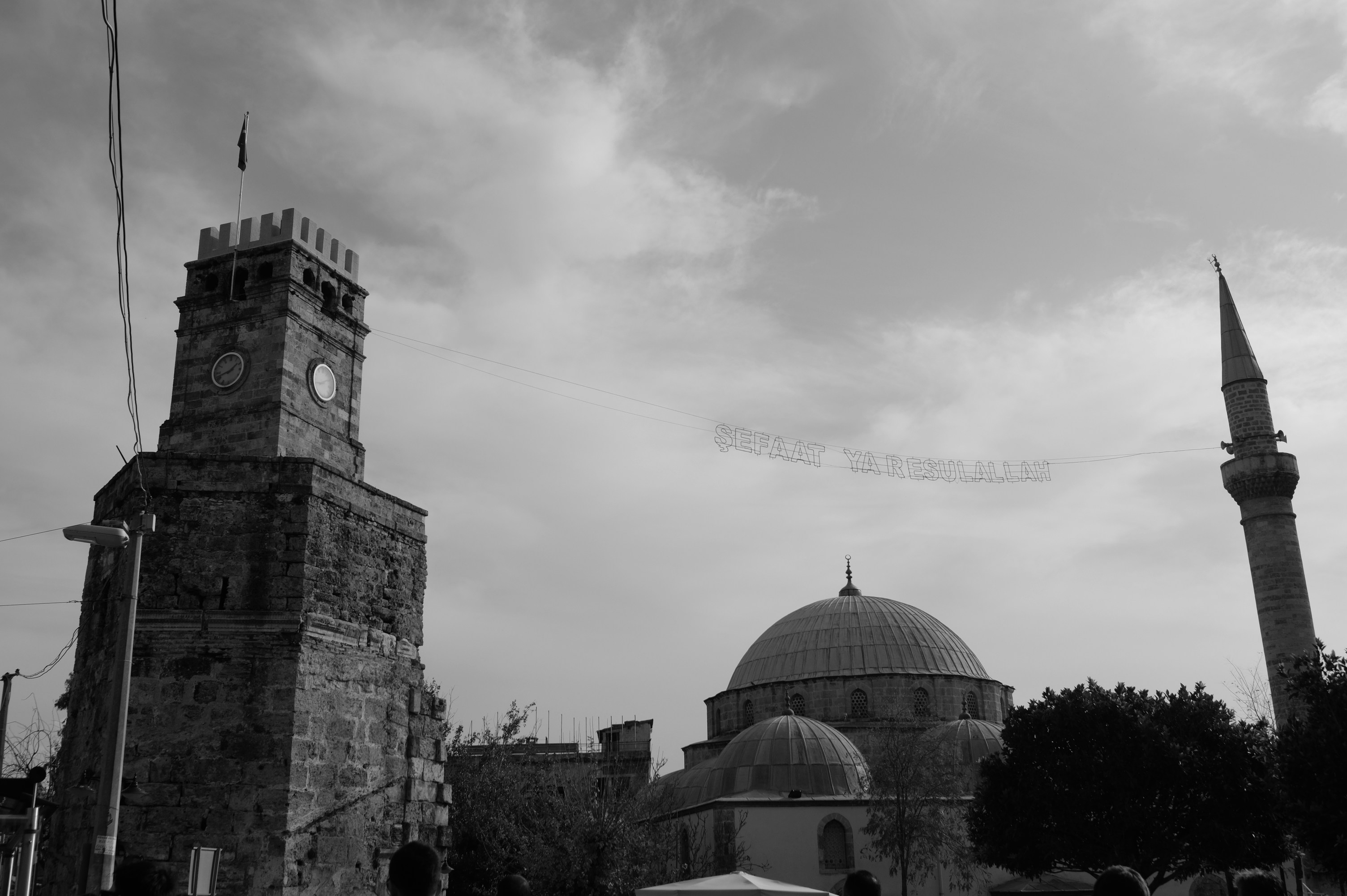 Historic clock tower and mosque under cloudy sky.