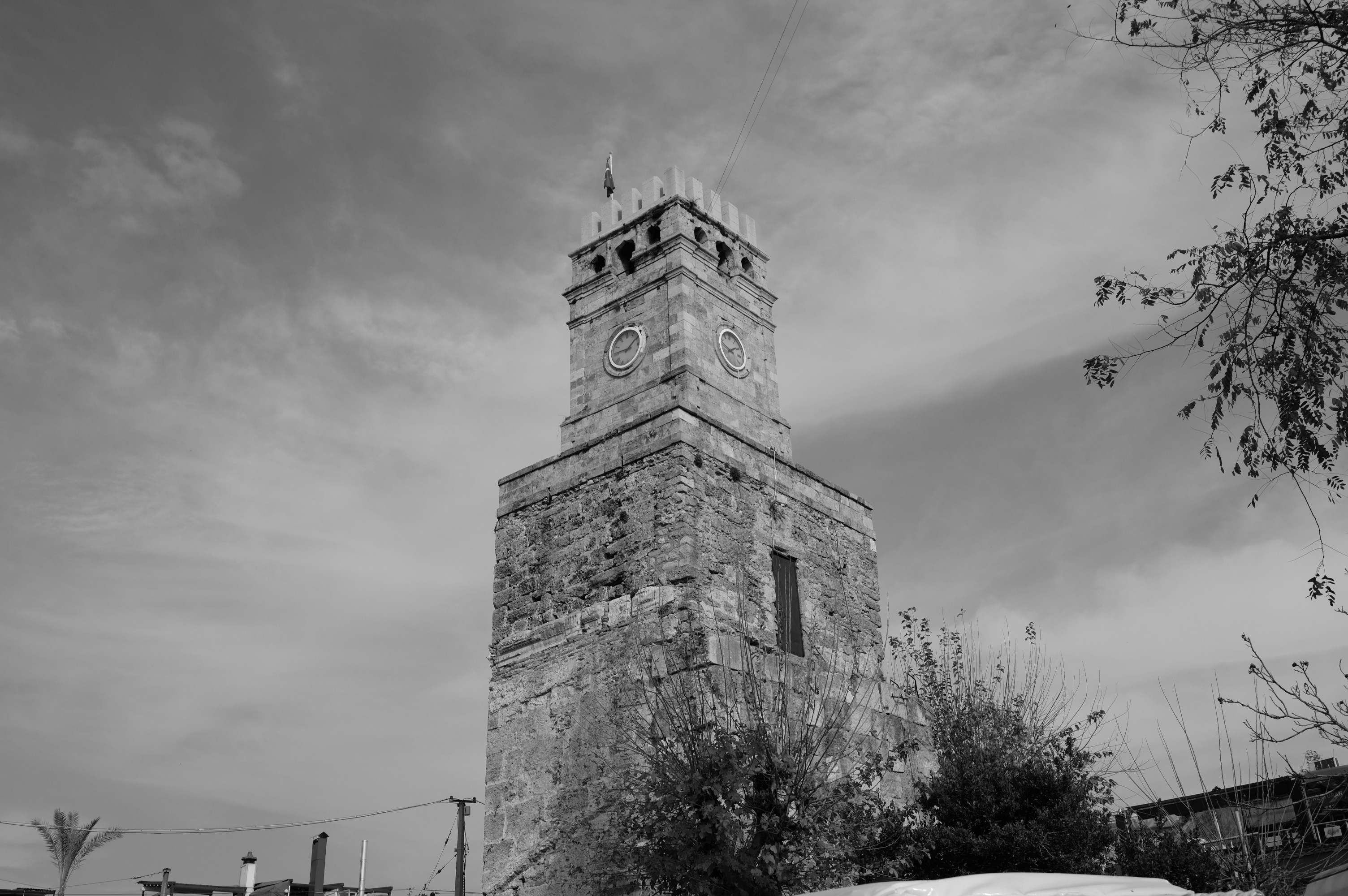 Historic stone tower rising against a dramatic sky, surrounded by foliage. The structure showcases architectural details of a bygone era.