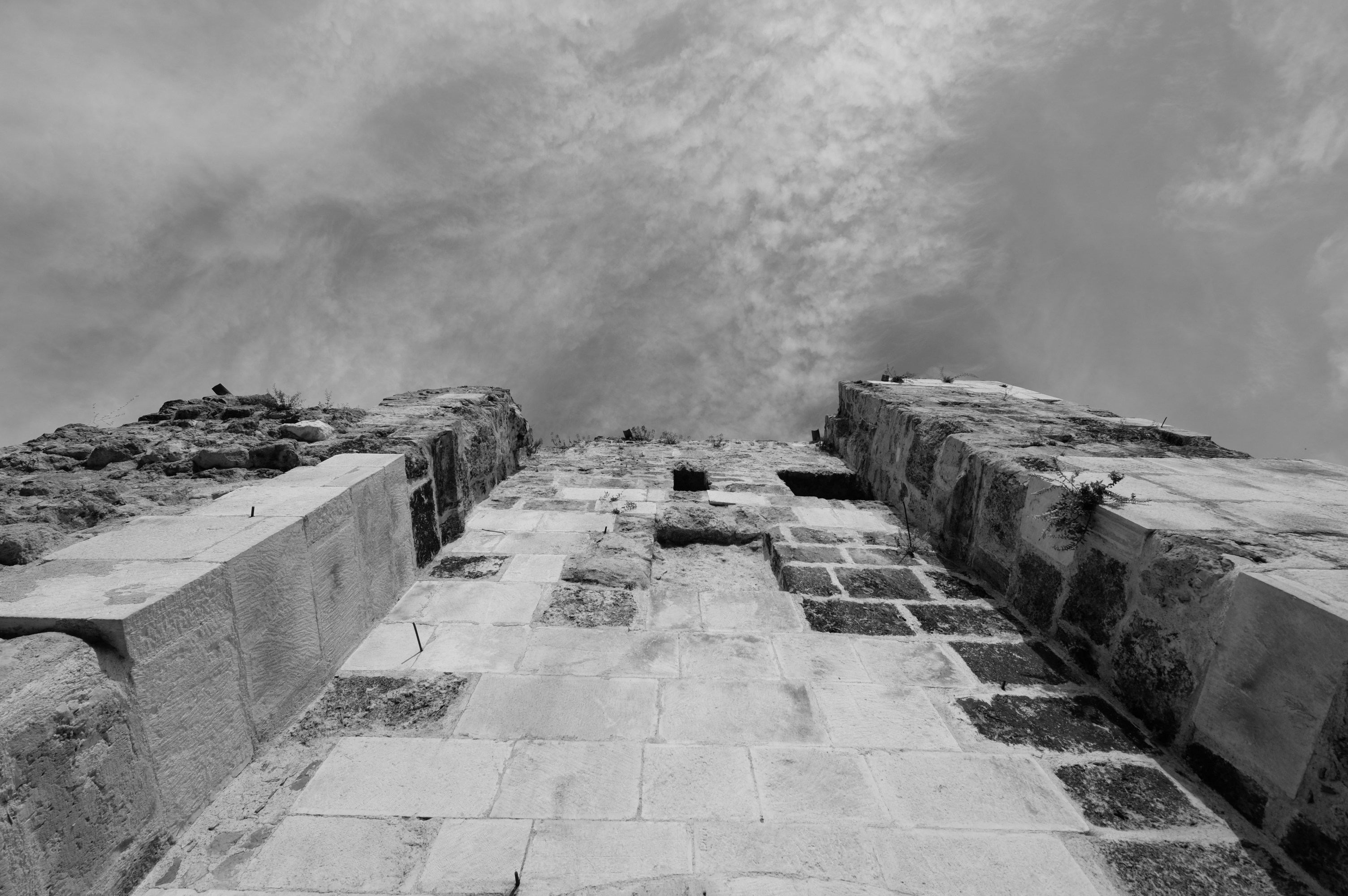 Looking up at ancient stone ruins against cloudy sky