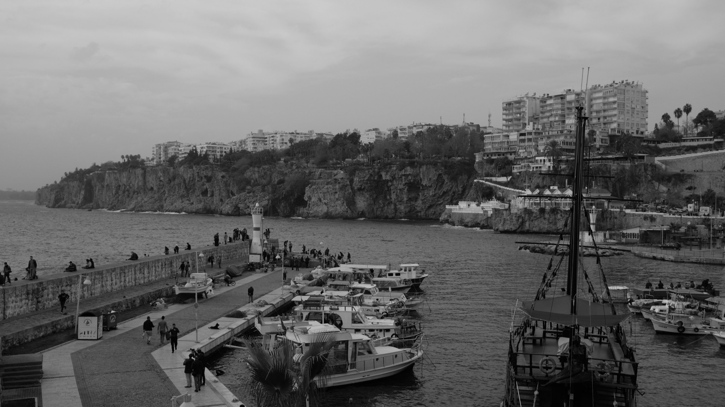Harbor Quiet: Boats Rest Along a Cliffside Promenade in Monochrome