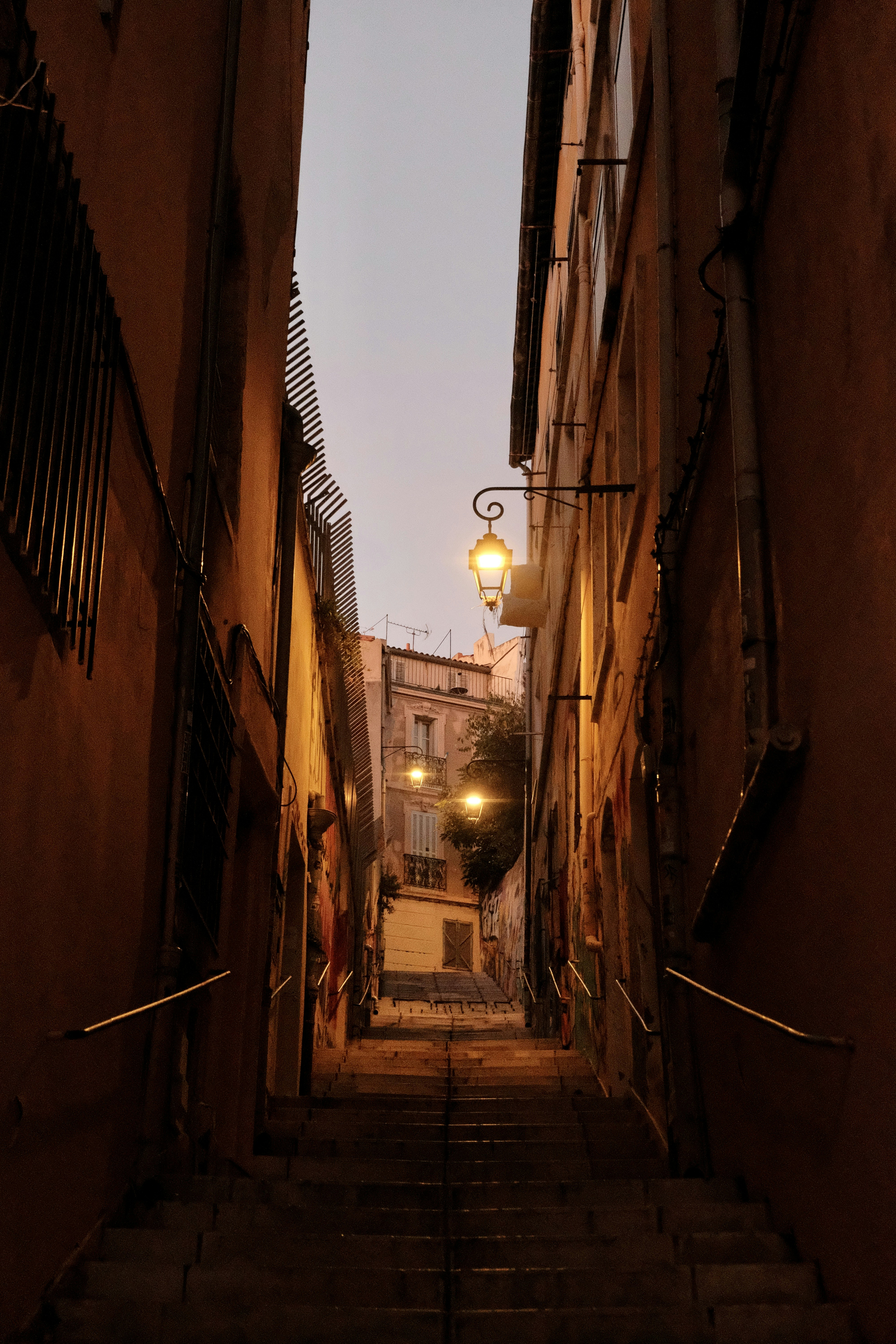 Narrow cobblestone street with gas lamps at dusk