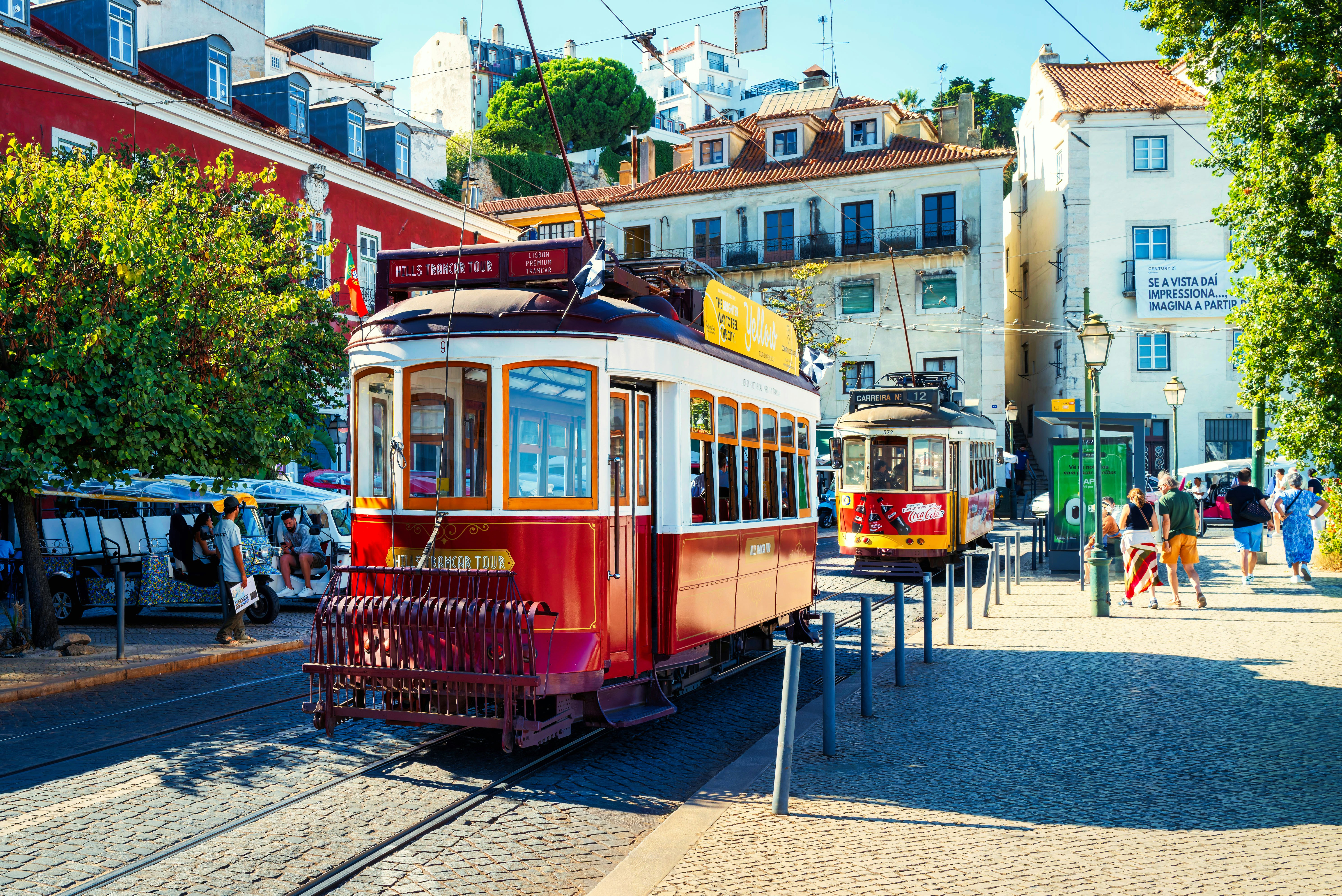 Colorful trams navigate the cobblestone streets of Lisbon, surrounded by vibrant buildings and bustling pedestrians.